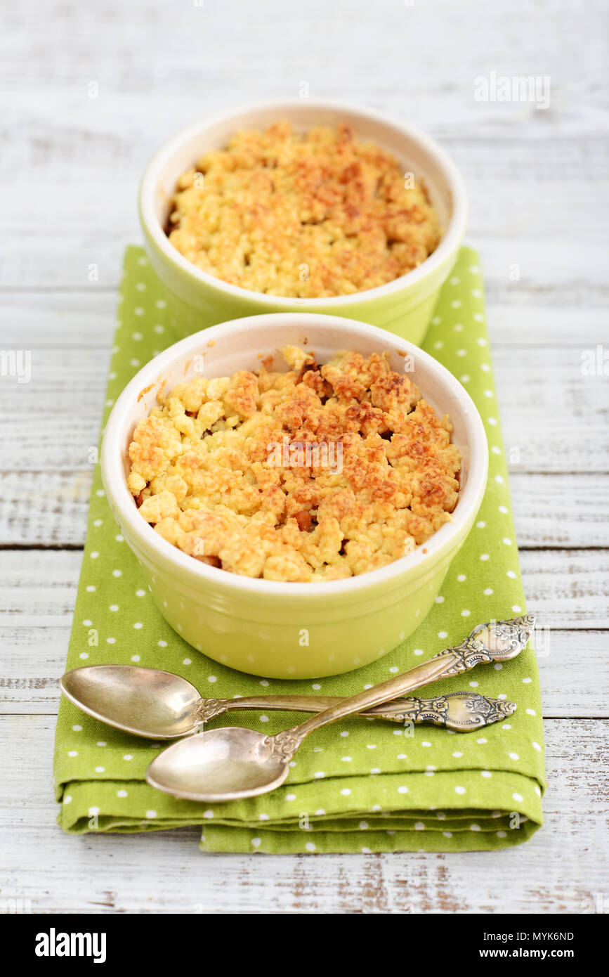 Apple crumble in small baking dish with fresh apples on wooden ...