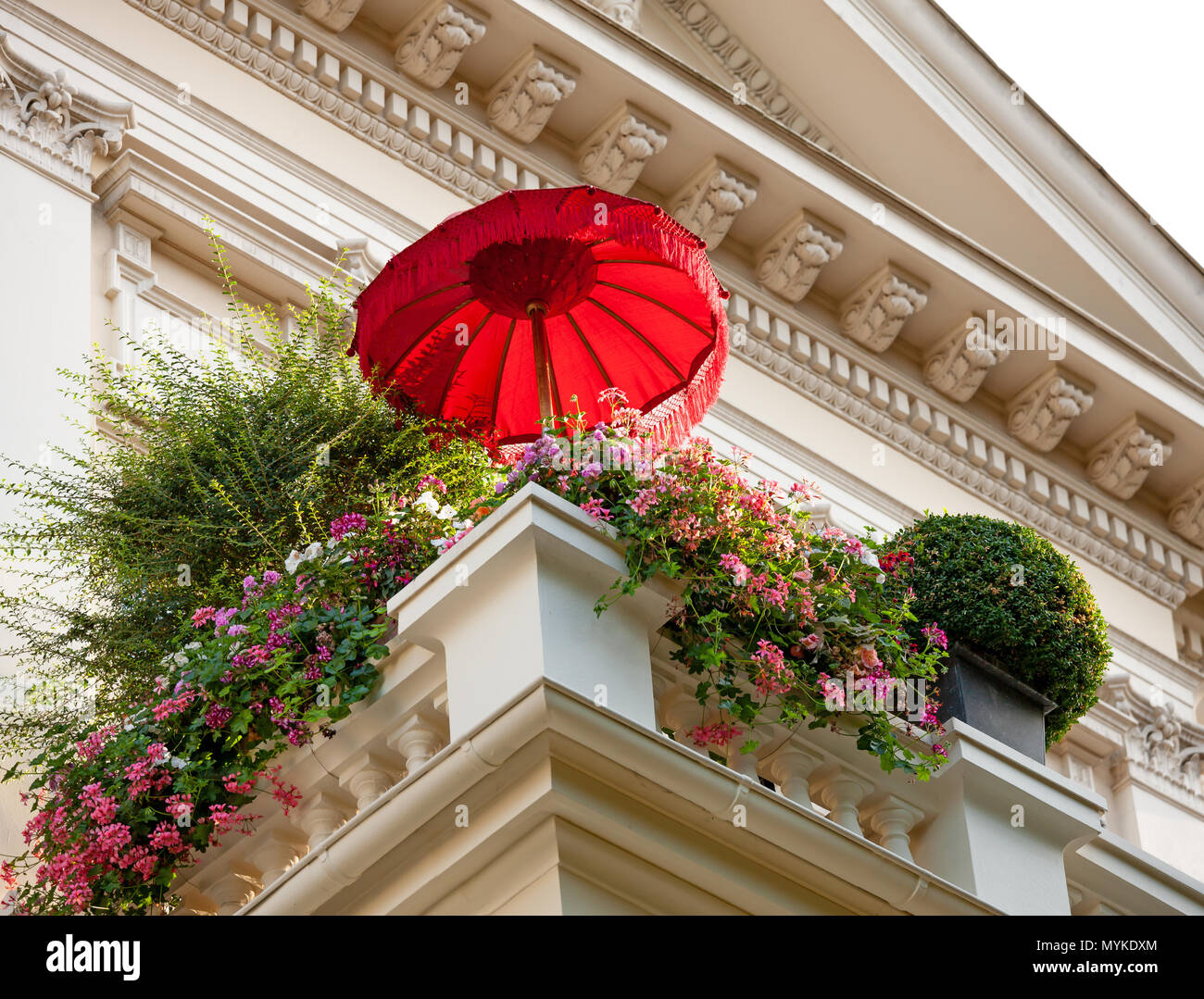 Red sun umbrella on the balcony of an elegant, neo classic building ...