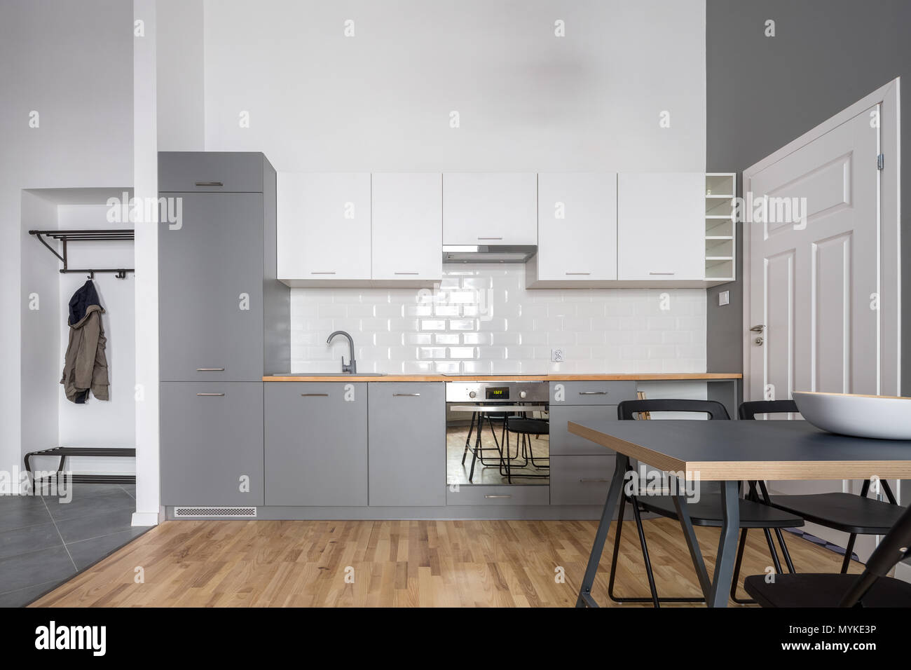 Open kitchen in gray and white with simple table Stock Photo - Alamy