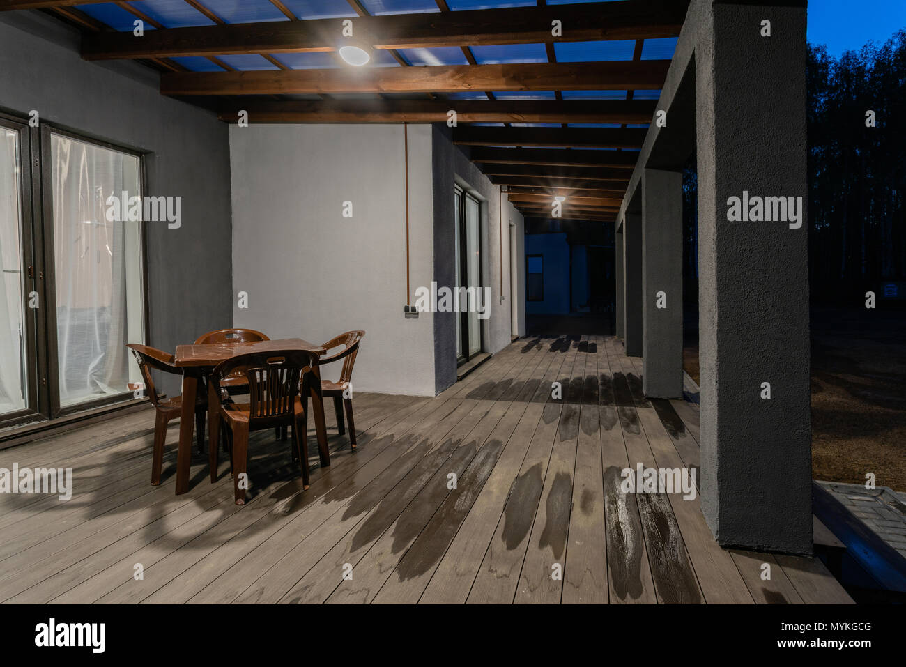 Side view of an open veranda in front of a modern forest cottage. Pine ...