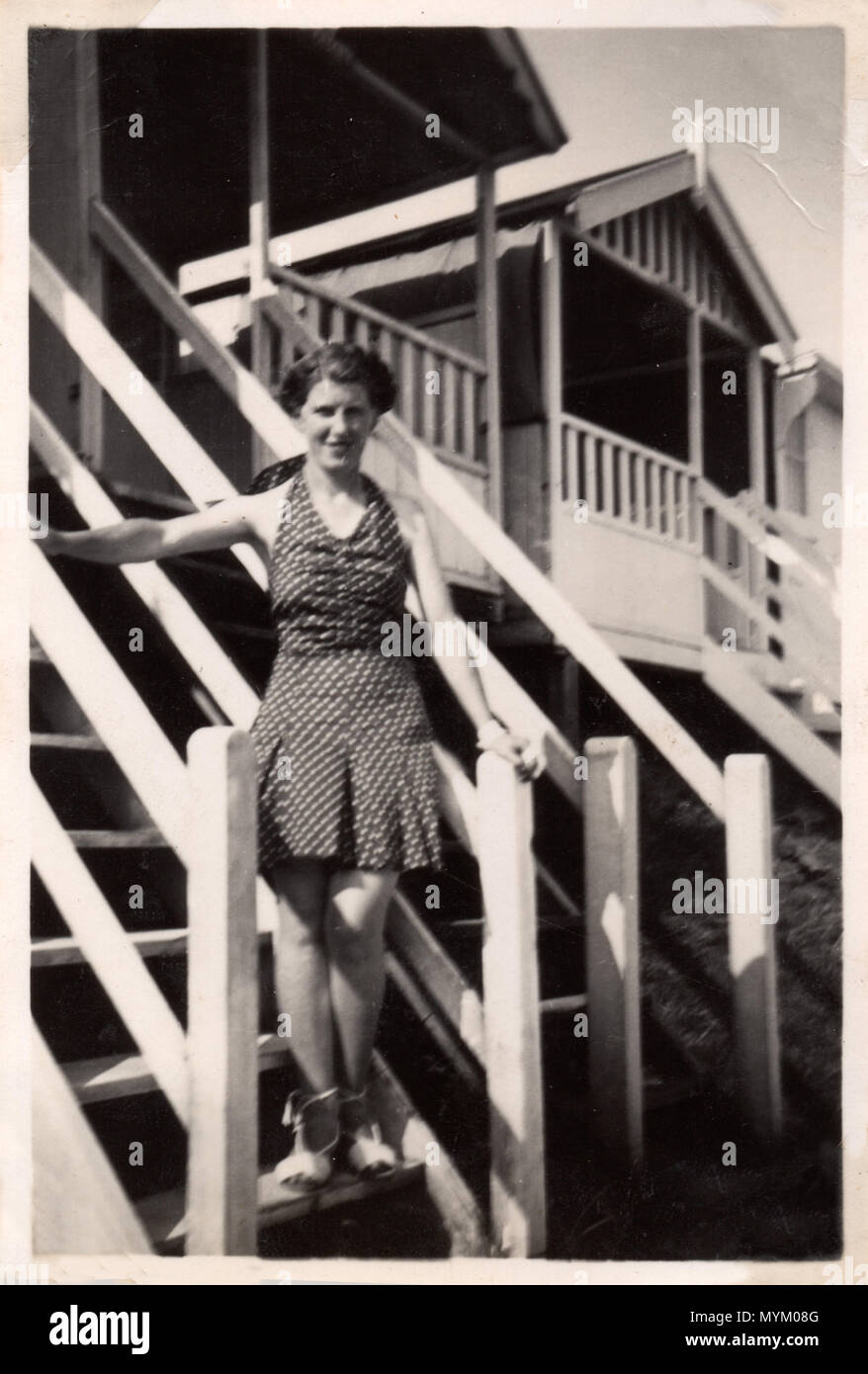 Woman wearing a fashionable swimsuit, poses on the steps of a beach hut ...