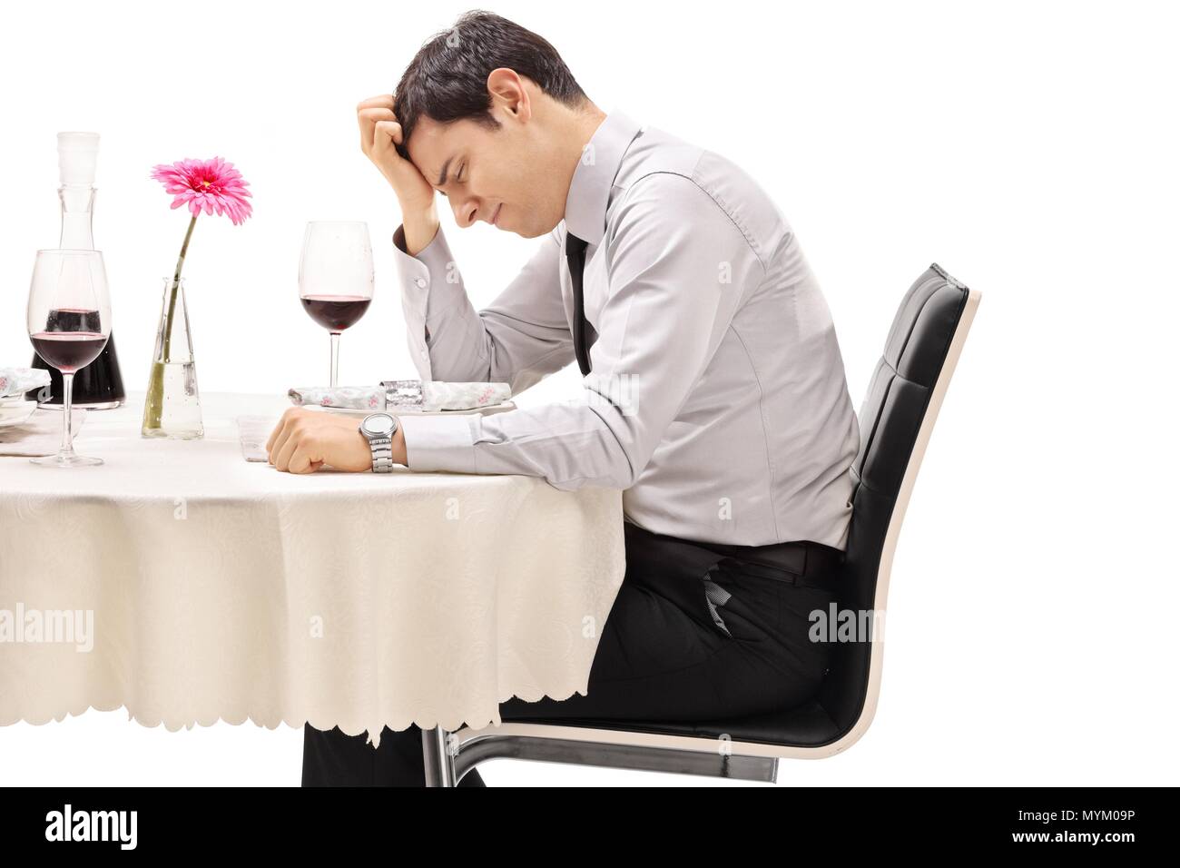 Disappointed young man sitting at a restaurant table isolated on white ...