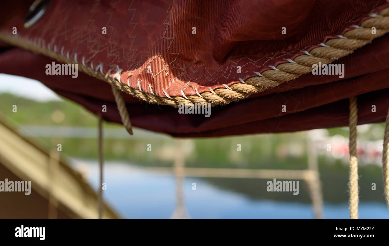 Stitches and rope on a sail with blurred water in the background Stock ...