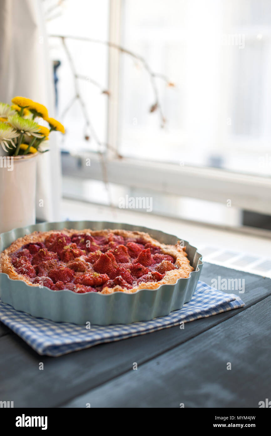 Open cake with strawberries in blue bowl for breakfast, near the window ...