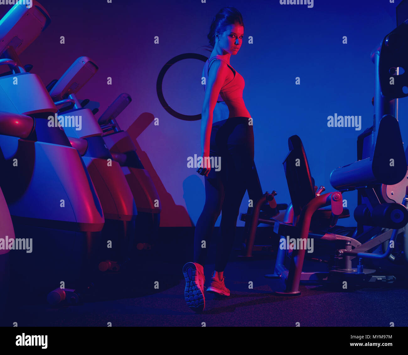 Female fitness model walking between two rows of exercise machin Stock ...