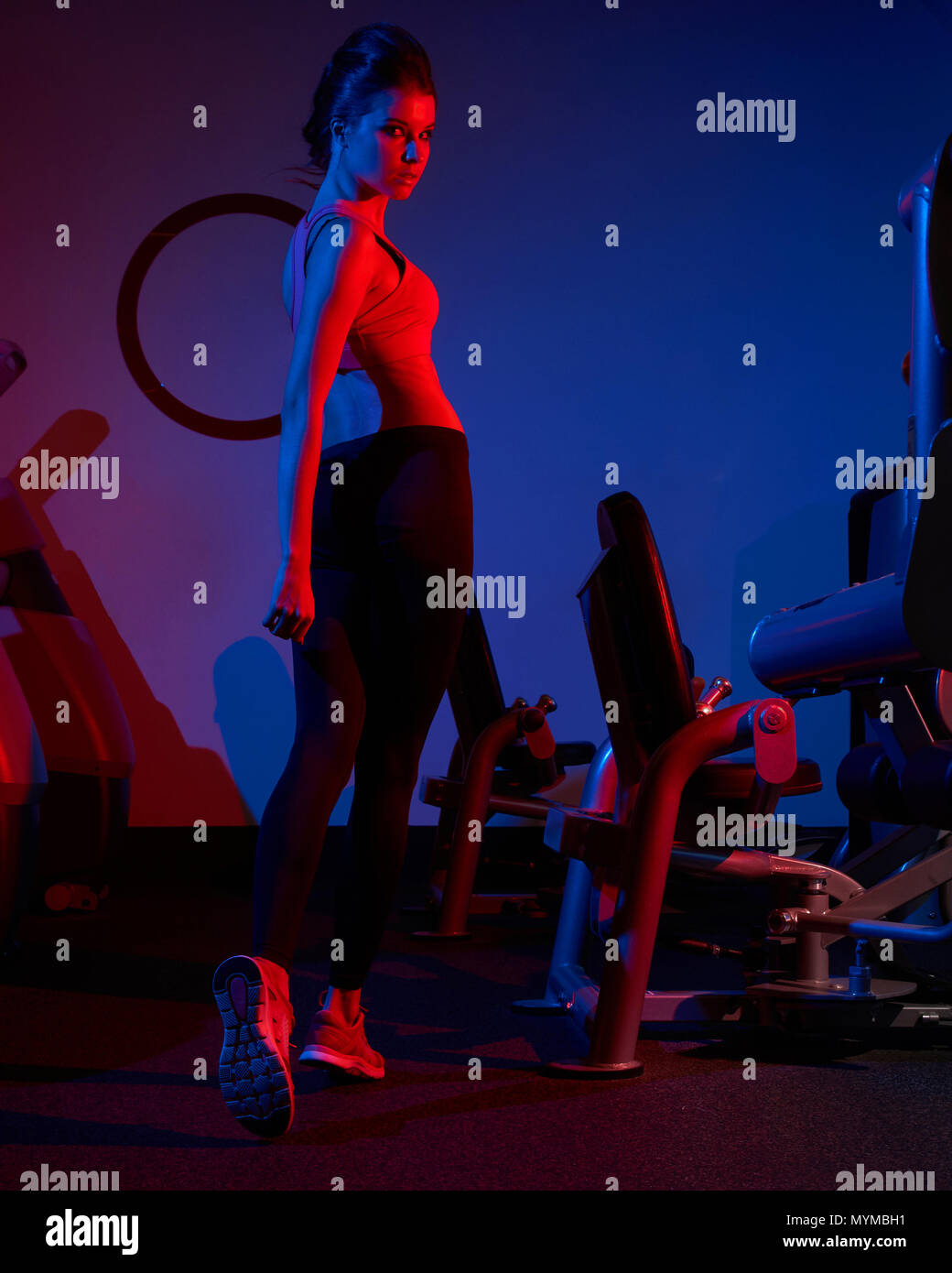 Female fitness model walking between two rows of exercise machin Stock ...