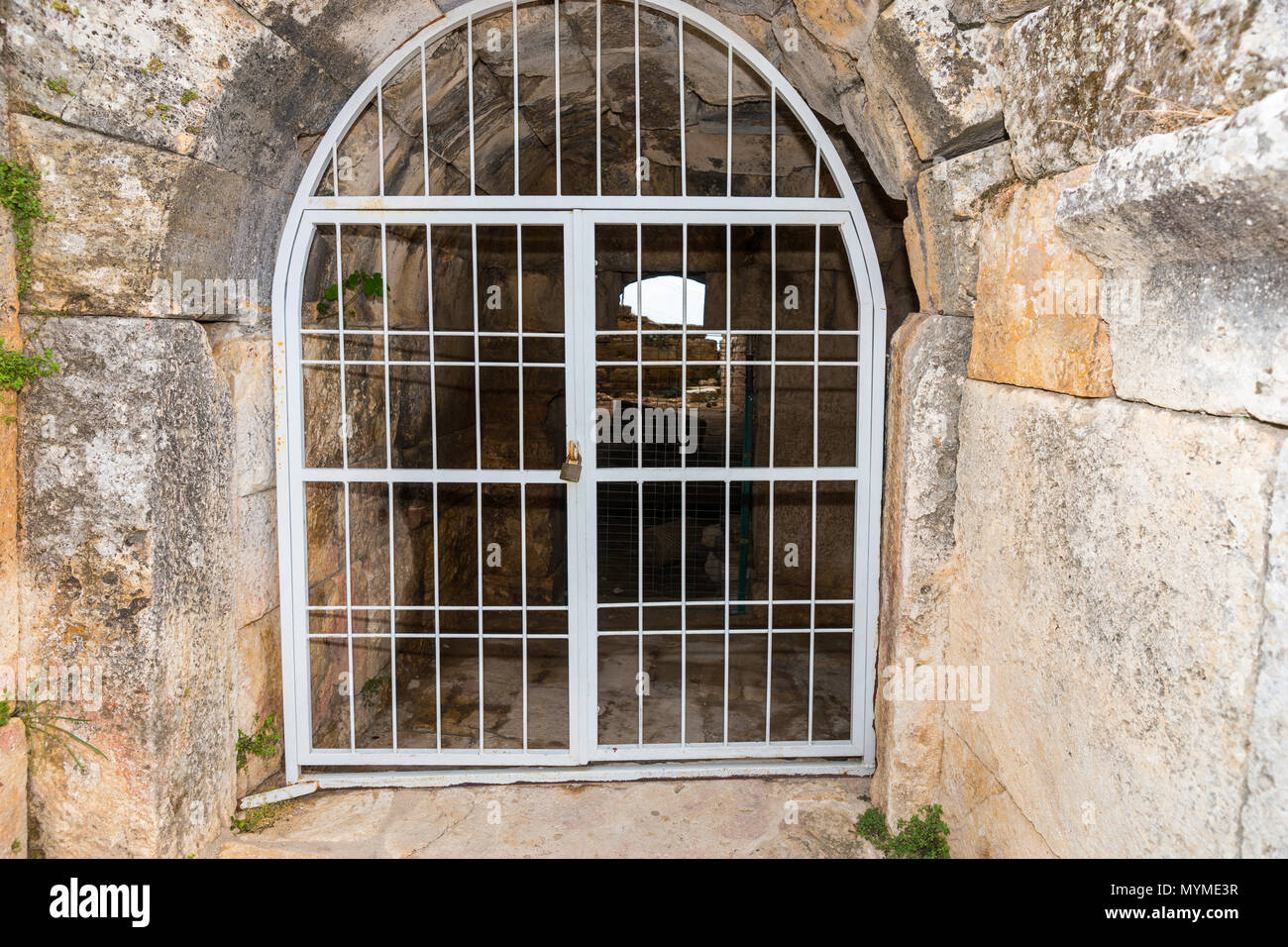 Entrance to an ancient vaulted stone passage or tunnel with locked ...