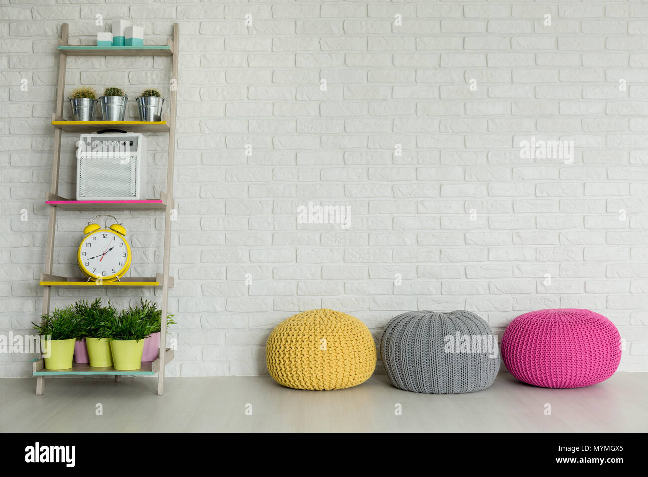 Light interior with DIY regale, colorful poufs and brick wall Stock ...