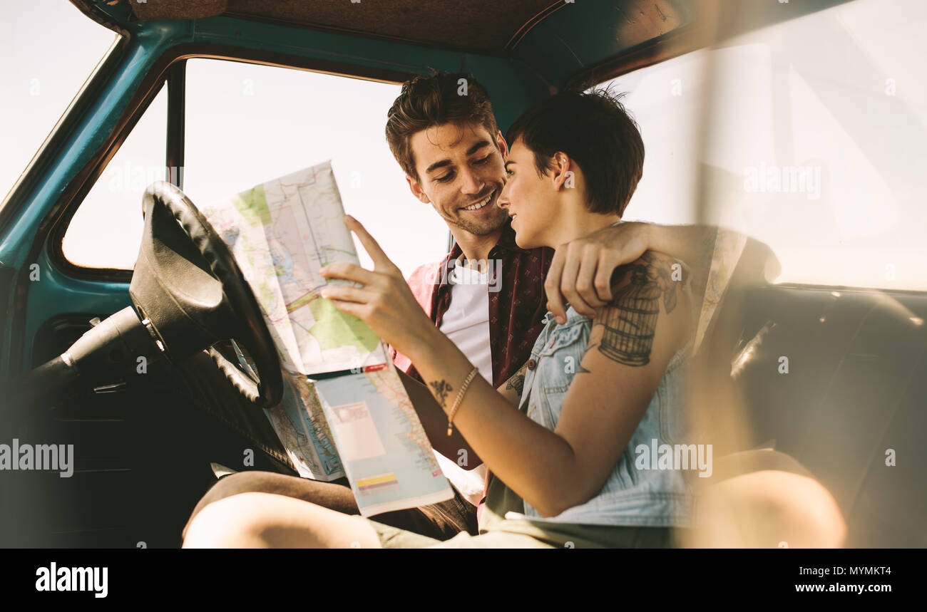 Couple looking at a map sitting in car. Smiling man and woman using map ...