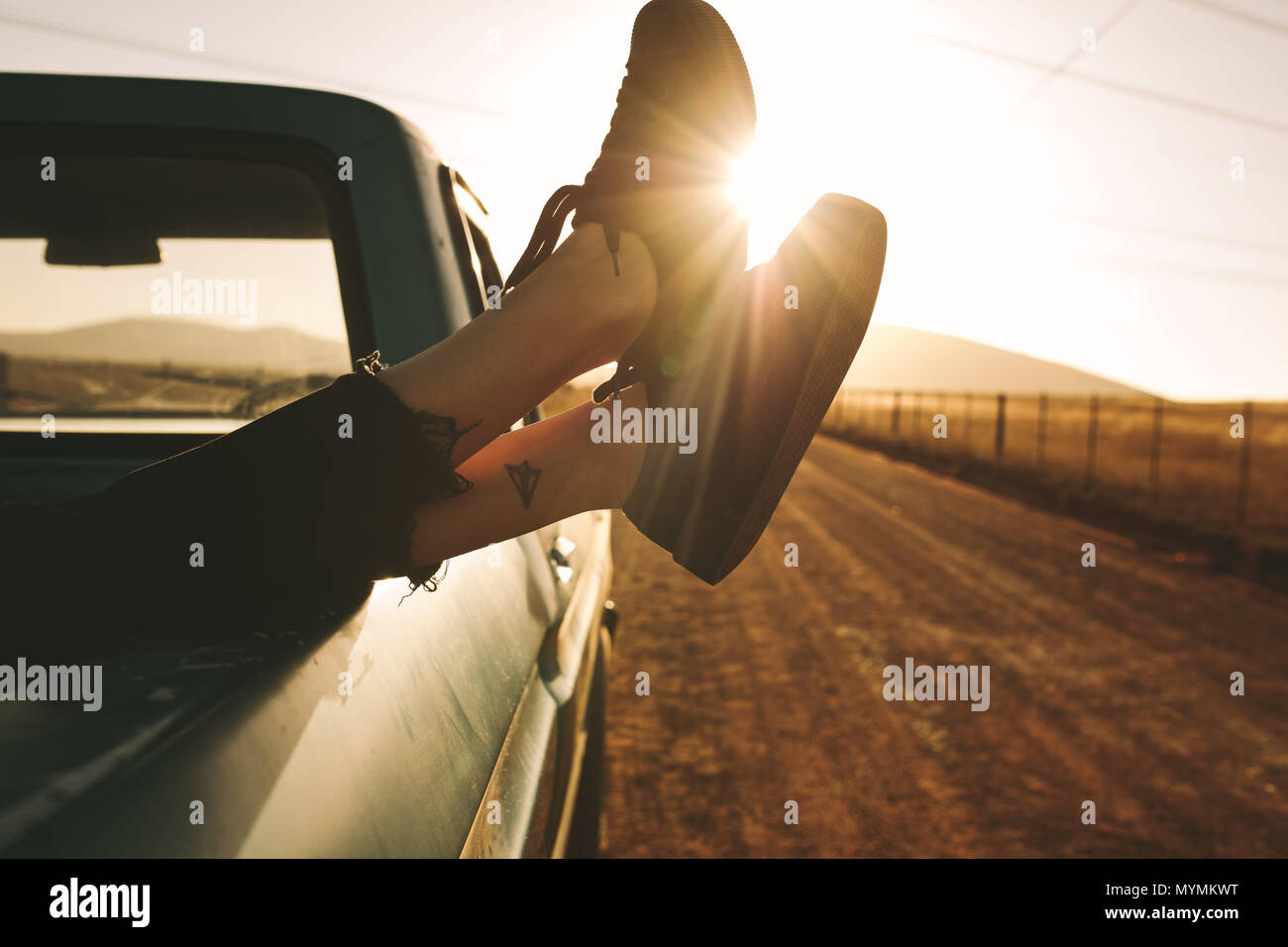 Close up of legs of a woman relaxing at the back of a pick up truck on ...
