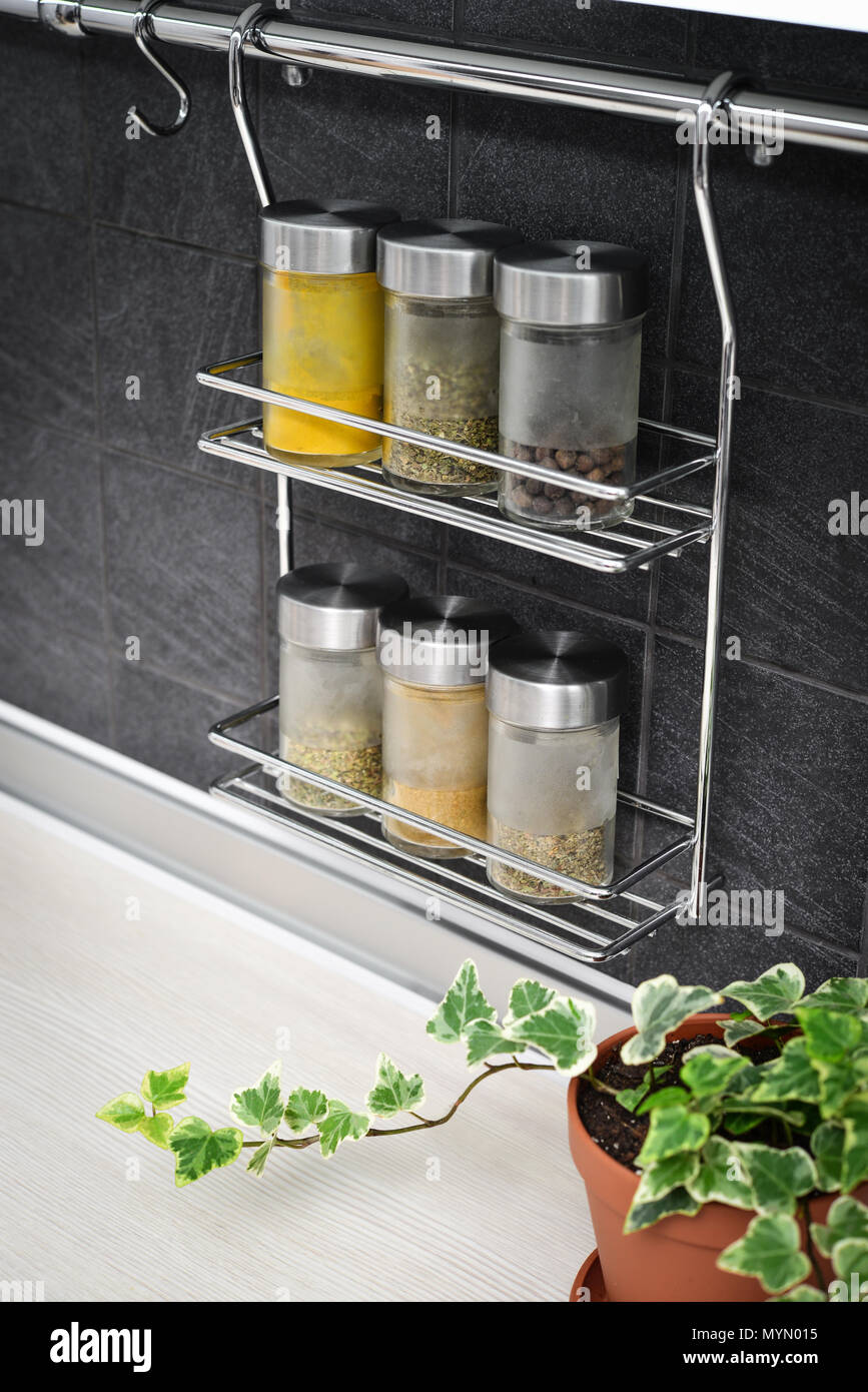 Jars of spices in hanging shelf in modern kitchen interior closeup ...
