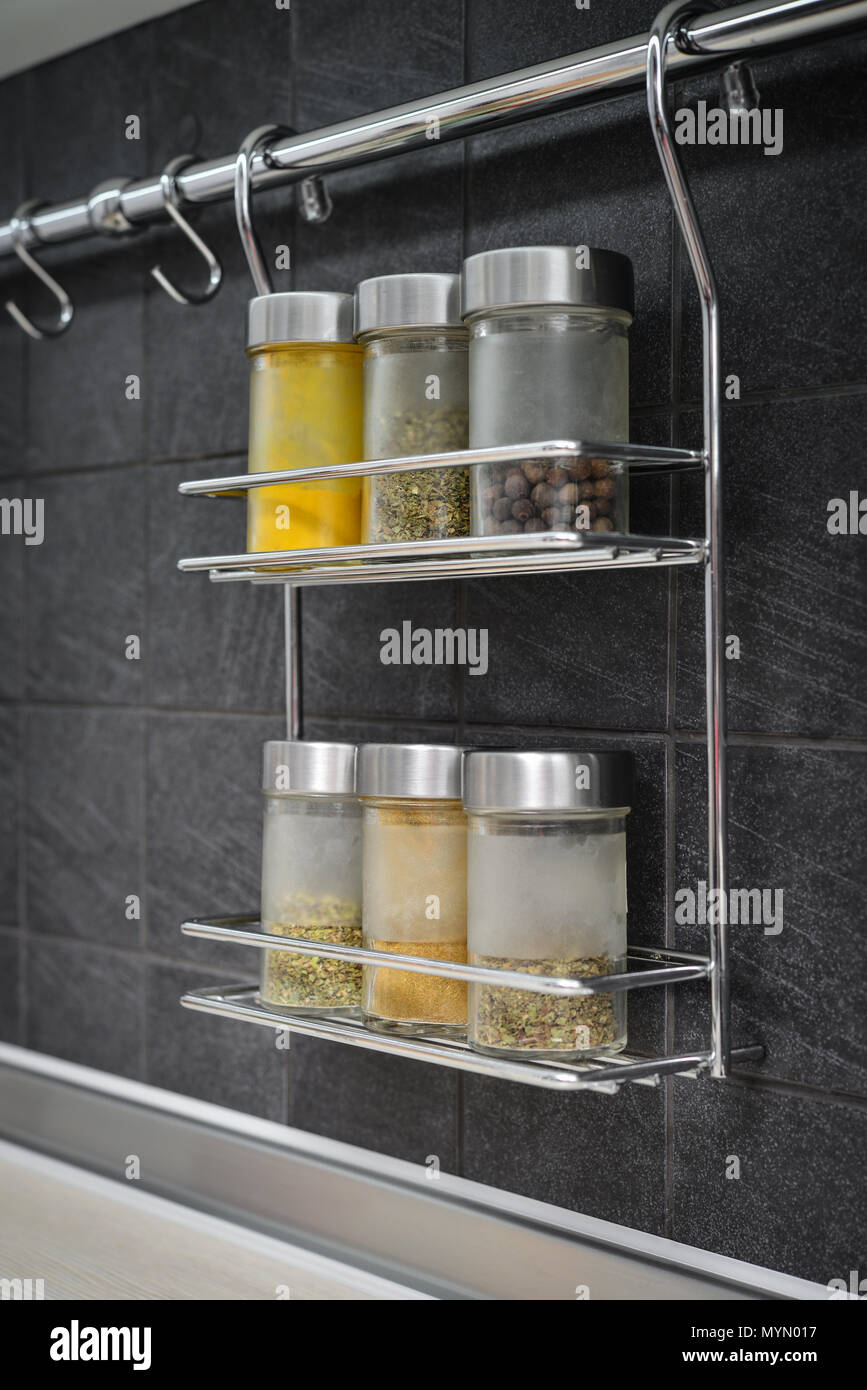 Jars of spices in hanging shelf in modern kitchen interior closeup ...