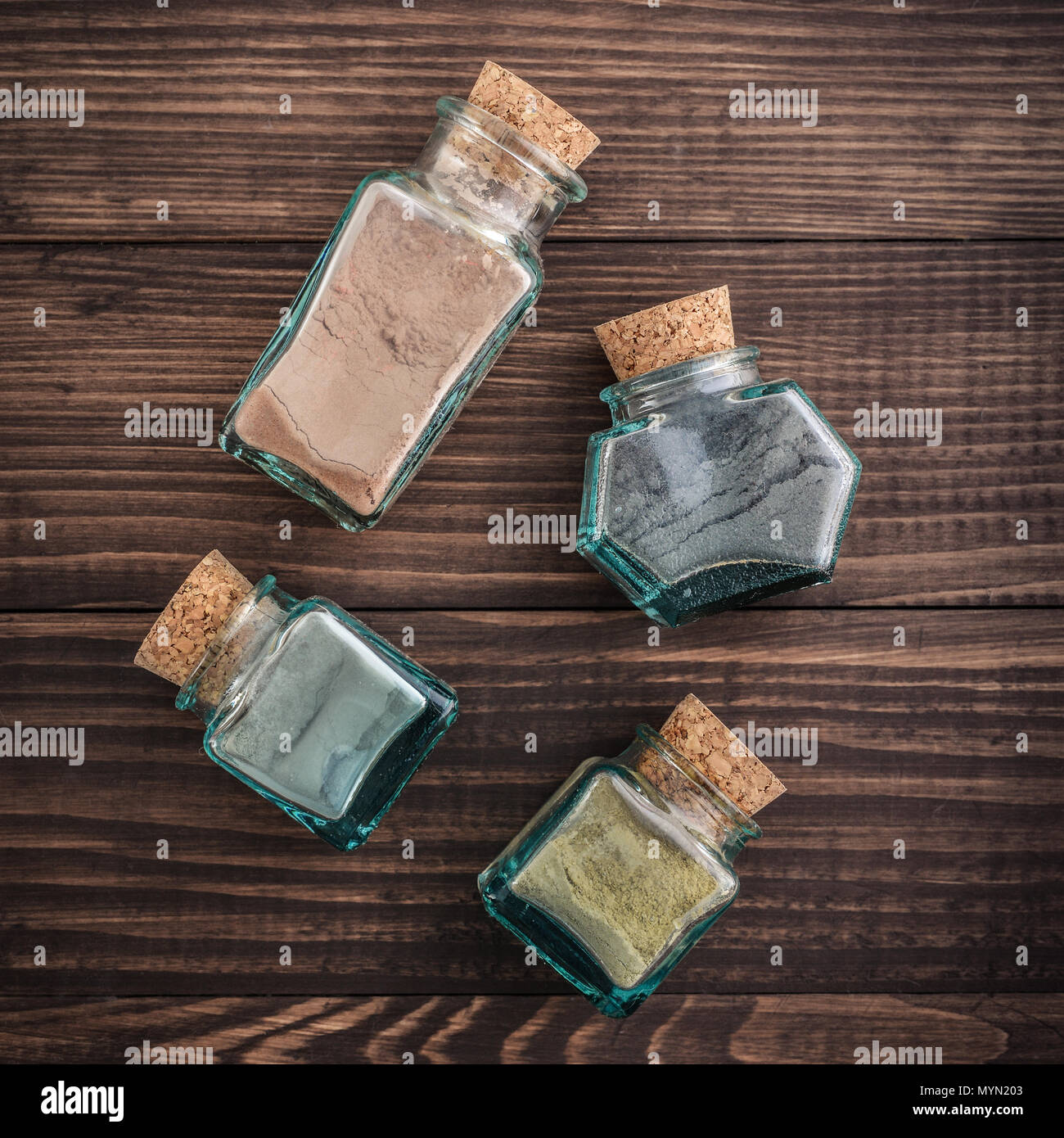 Different cosmetic clay in vintage jars on wooden background, top view ...