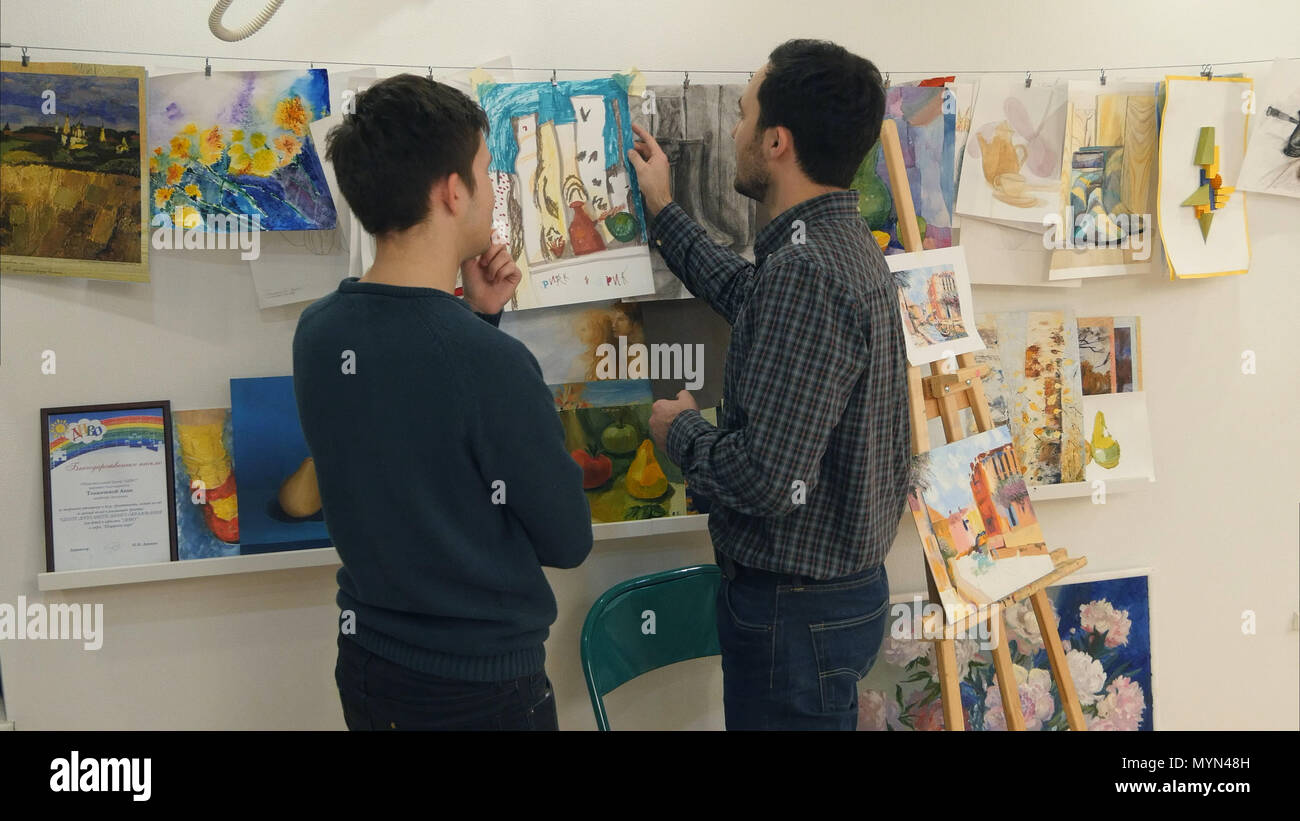 Two young men discussing paintings drawn by art students Stock Photo ...