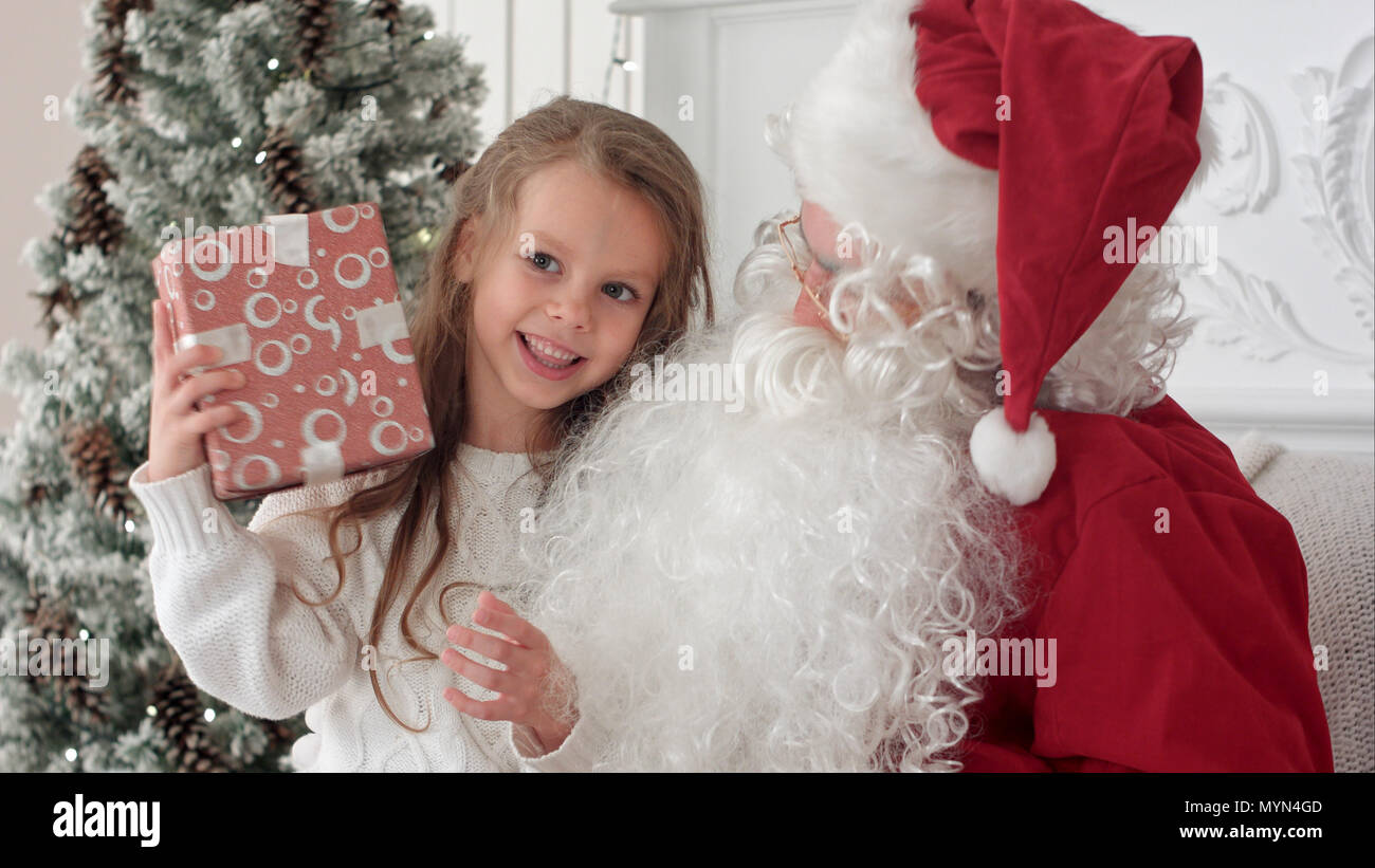 Litlle girl shaking her present from Santa trying to guess what is ...