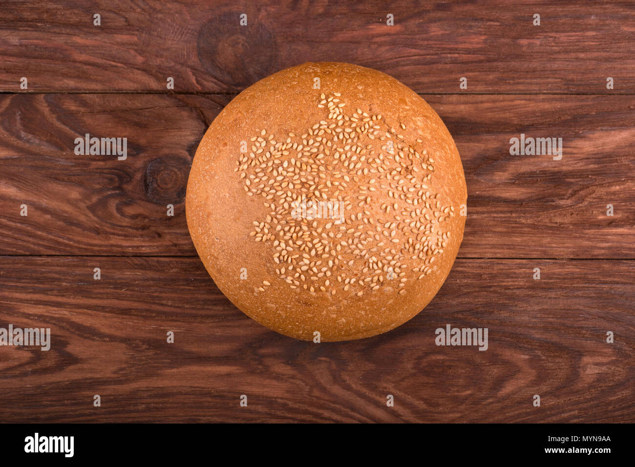 The fluffy bun with sesame seeds on a brown wooden table a top view ...