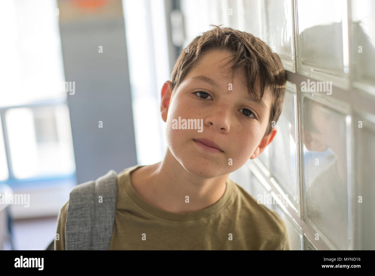 Student resting on the corridor of a school and playing with a mobile ...