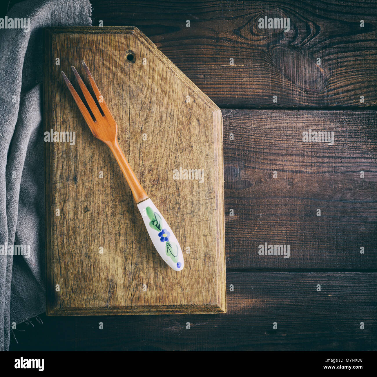 vintage wooden fork on a rectangular brown kitchen cutting board, top ...