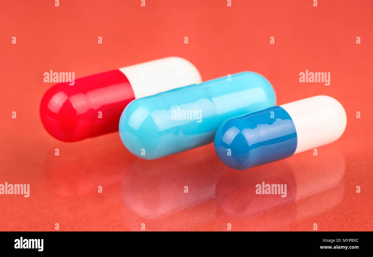 Three various color and shape capsules on a peachy background Stock ...