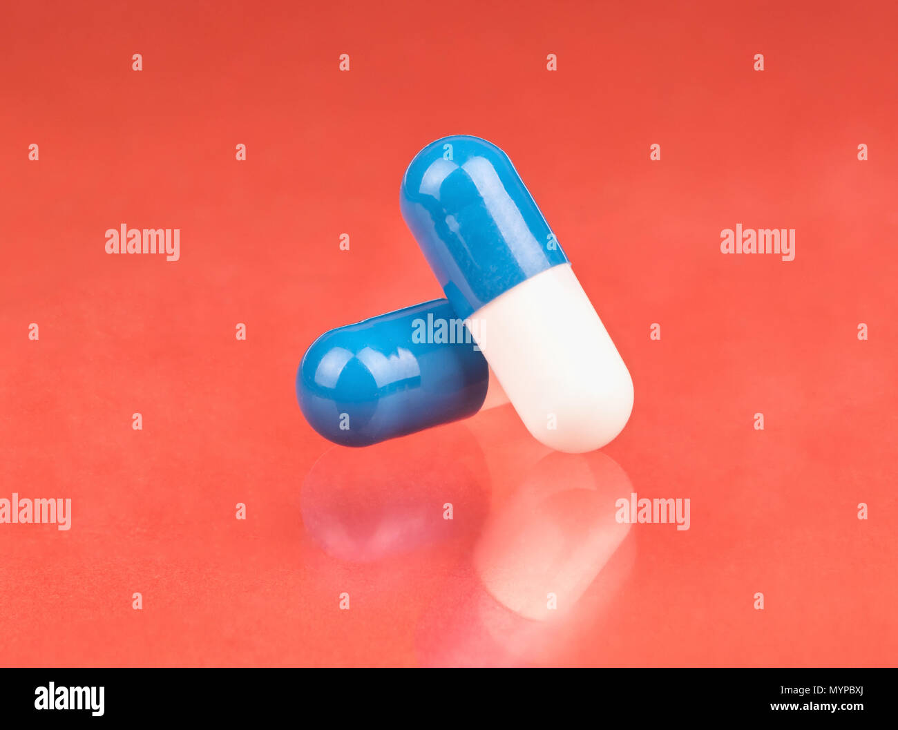 Two blue and white capsules crossed on peachy background Stock Photo ...
