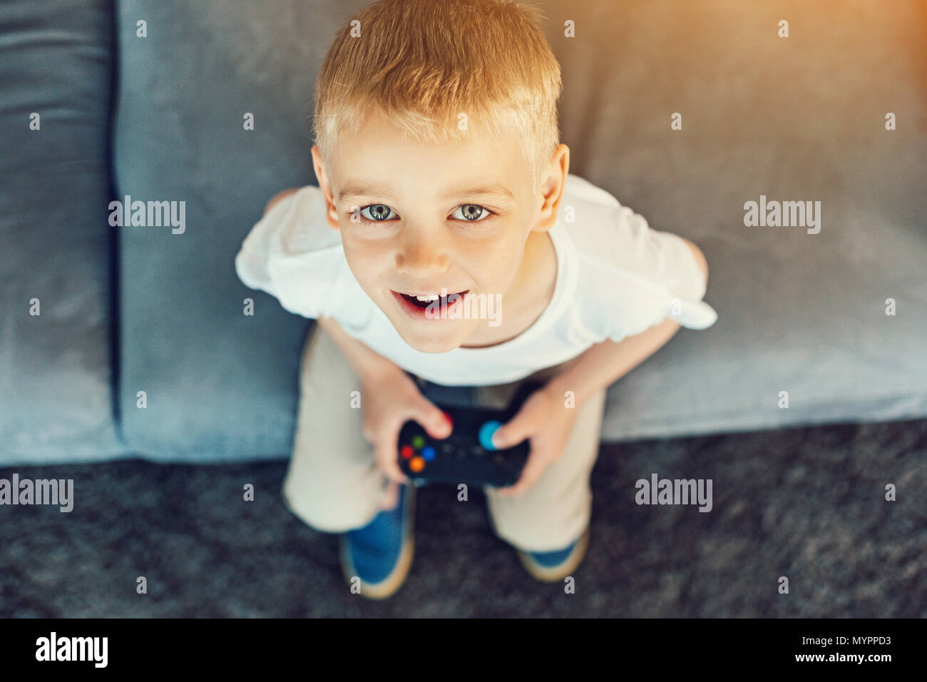 Playful boy sitting with a games console Stock Photo - Alamy