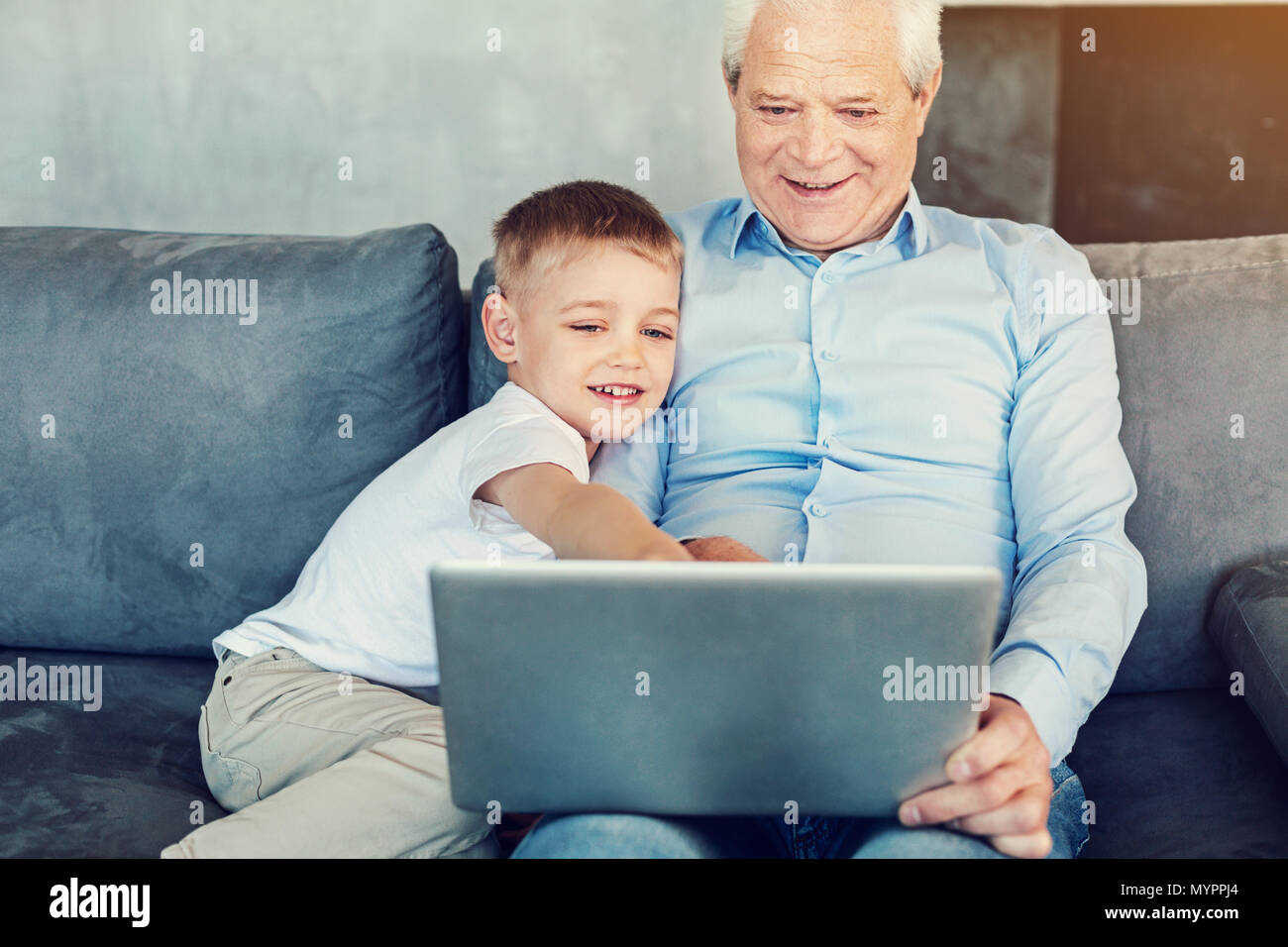 Happy boy showing his grandpa a new laptop Stock Photo - Alamy