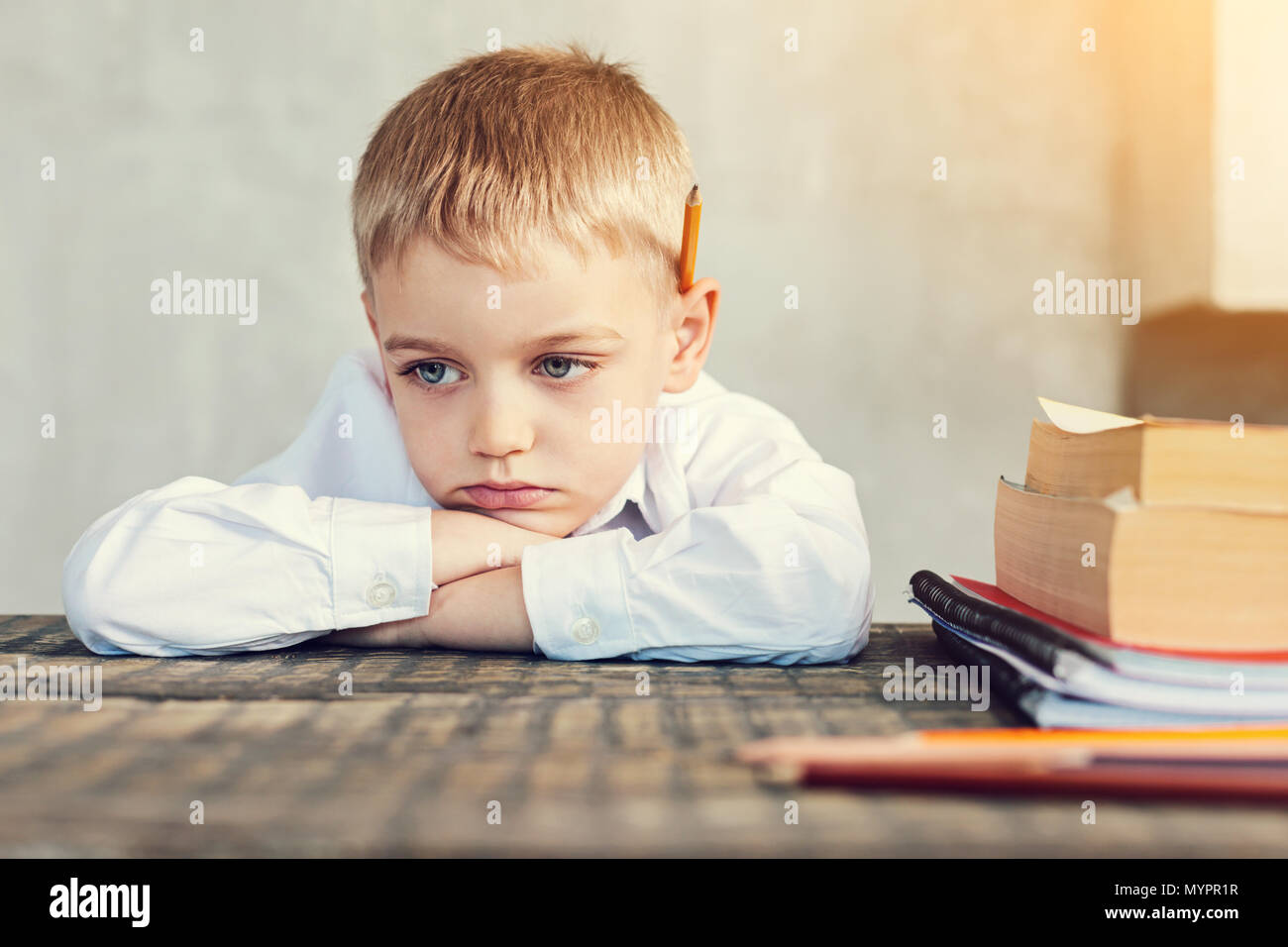 Sad little boy sitting at the table Stock Photo - Alamy