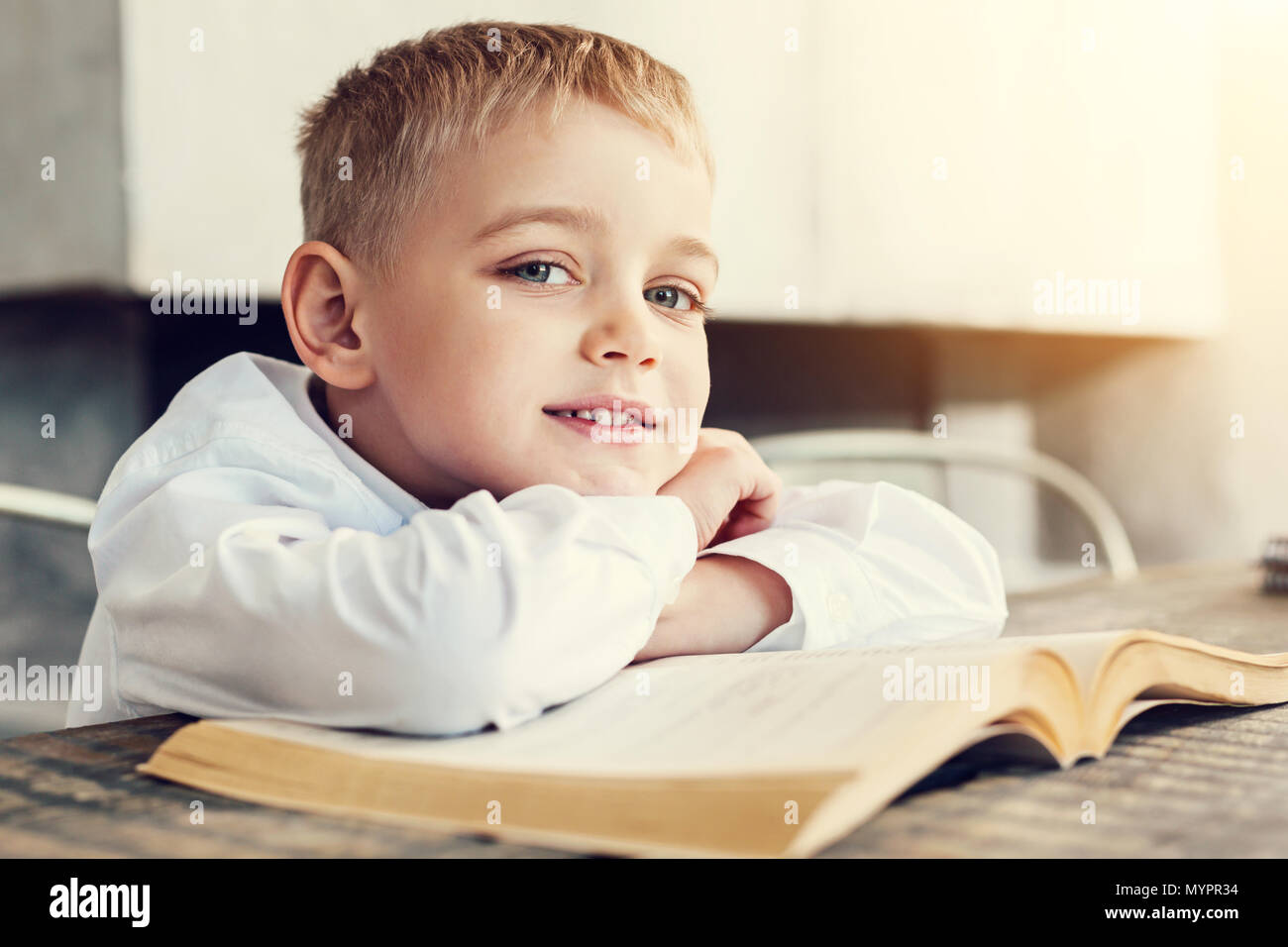 Smiling pretty pupil sitting with his book Stock Photo - Alamy