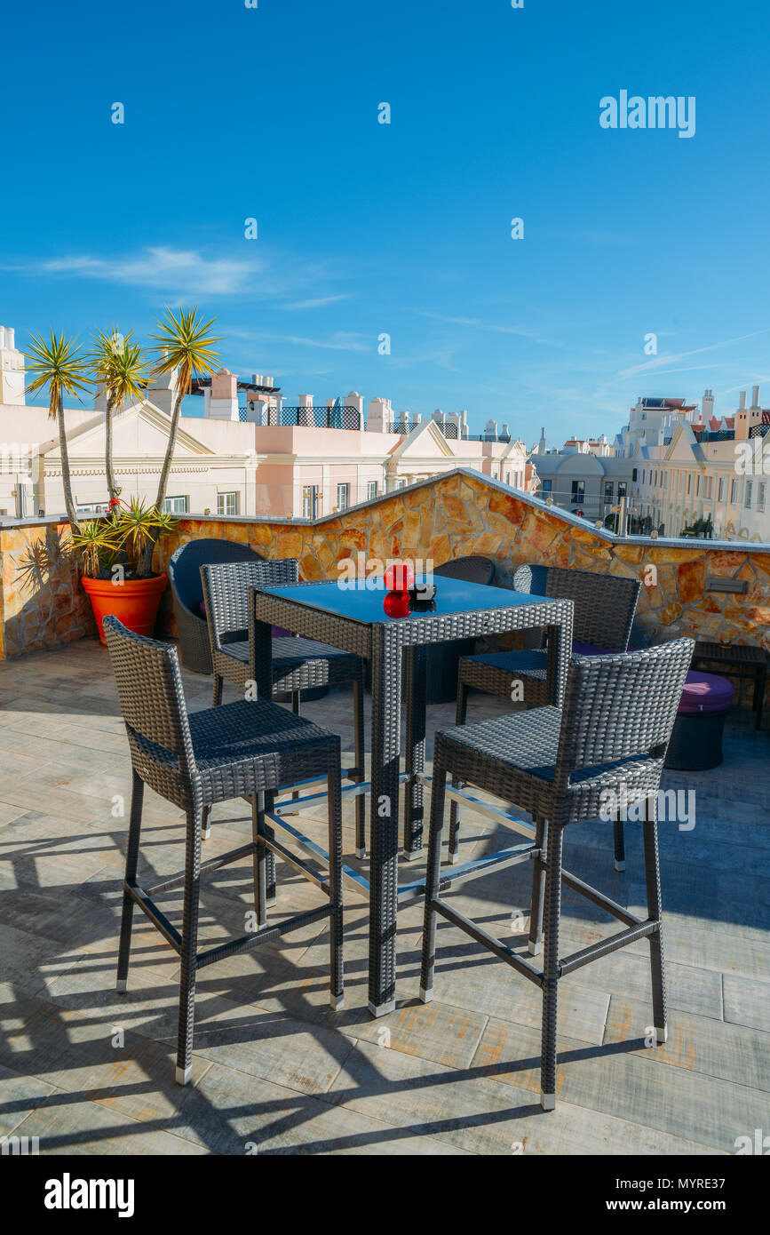 Table and chairs at a patio on a rooftop bar with sunny copy space ...