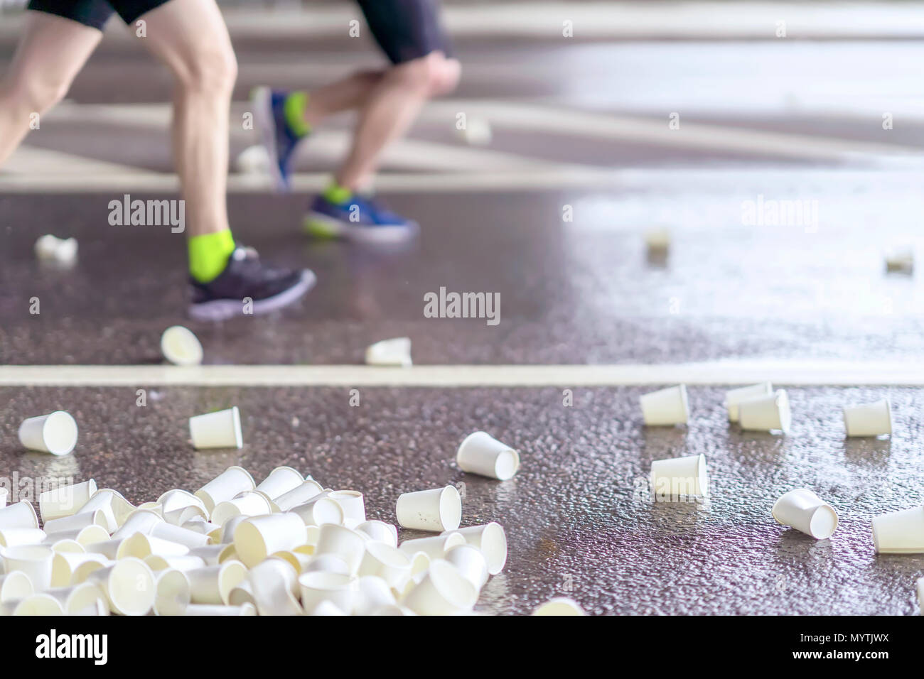 Feets of runners on marathon at service point, pile of used disposable ...