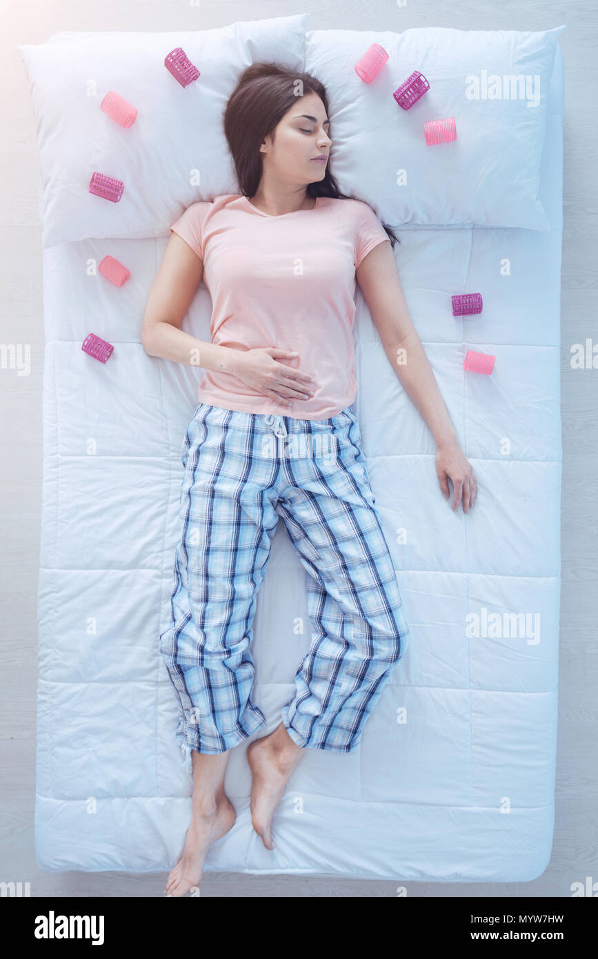 Young lady wearing pajamas sleeping with hair curlers in bed Stock ...
