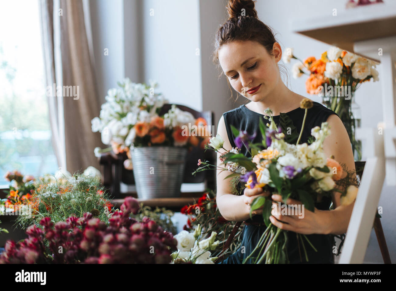 florist arranging a bouquet of beautiful colorful flowers inside her ...