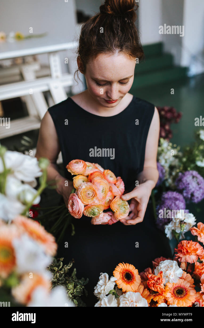 florist arranging a bouquet of beautiful colorful flowers inside her ...