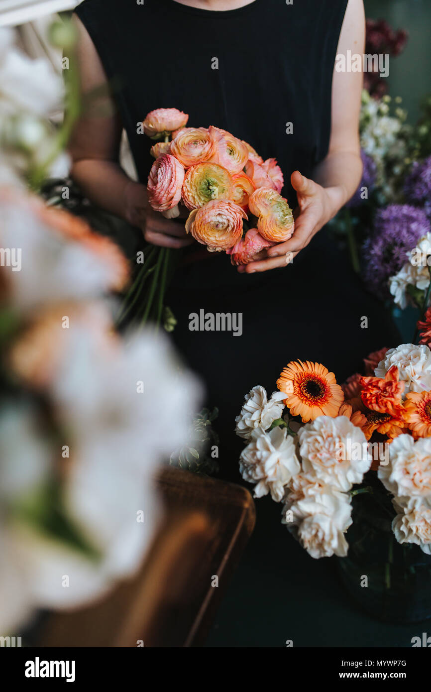 hands of florist arranging a bouquet of beautiful colorful flowers ...