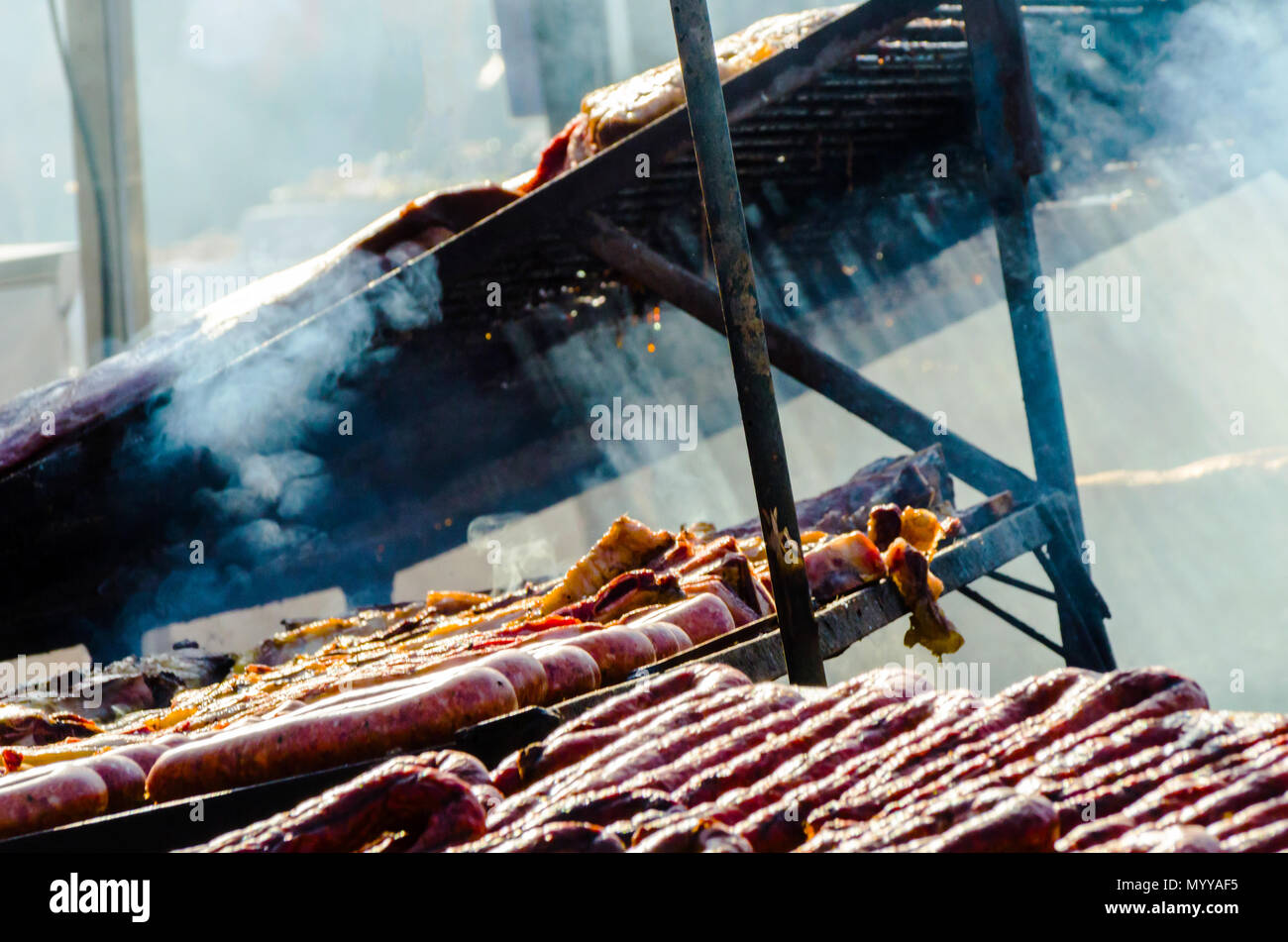 different types of meats and sausages stacked on a big grill while ...