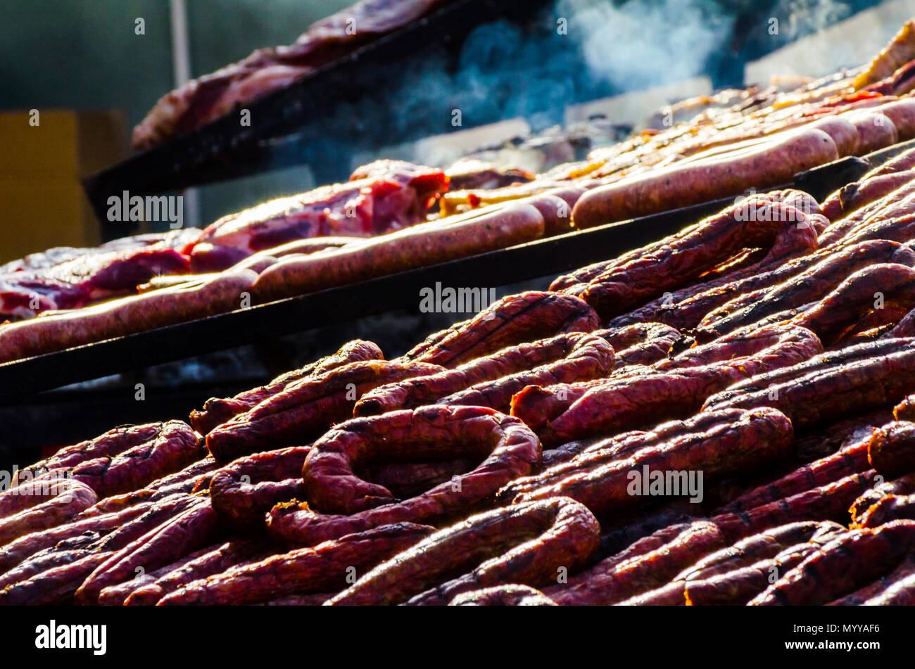 different types of meats and sausages stacked on a big grill while ...