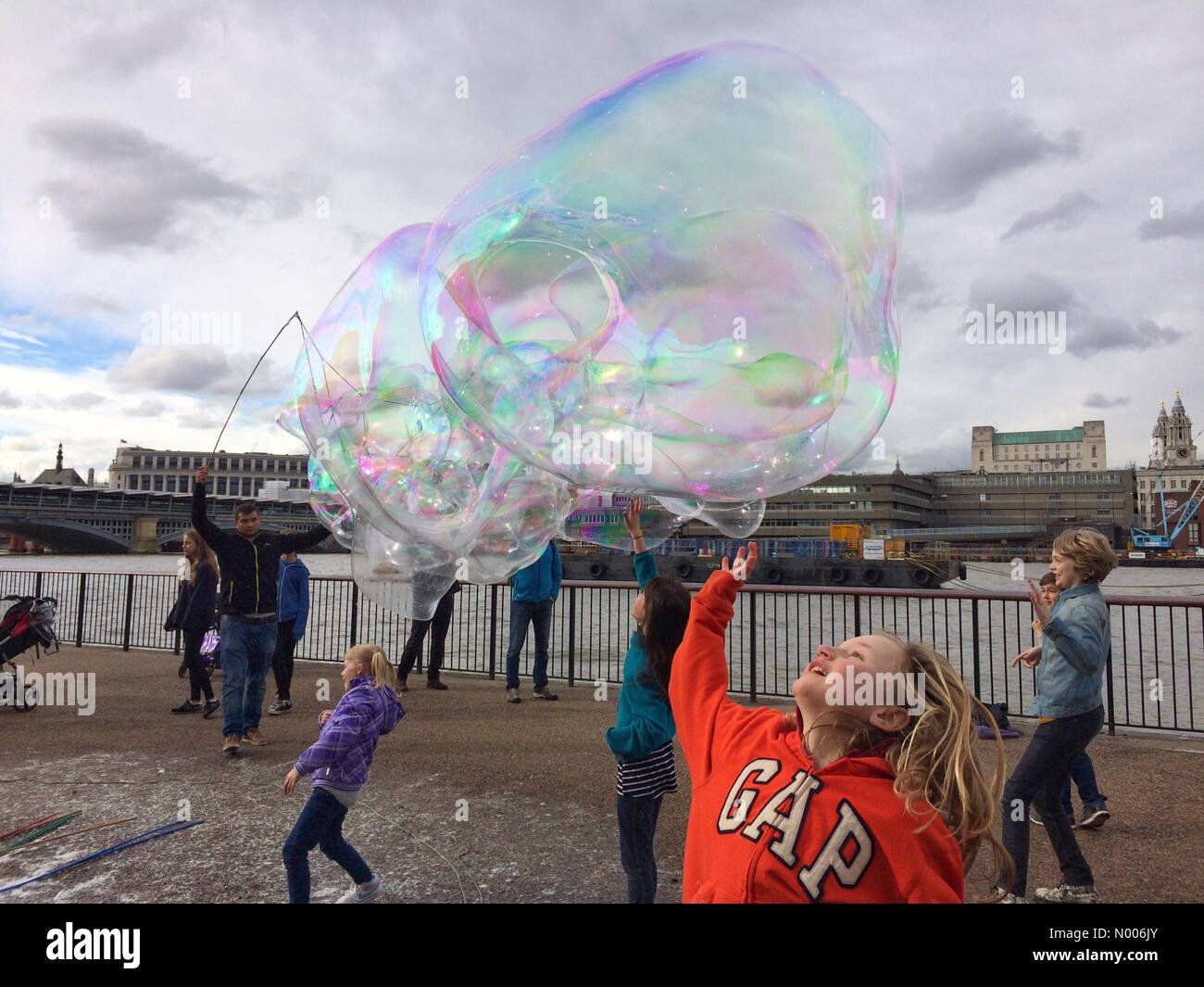 London, UK. 09th Apr, 2016. A busker entertains children by blowing ...