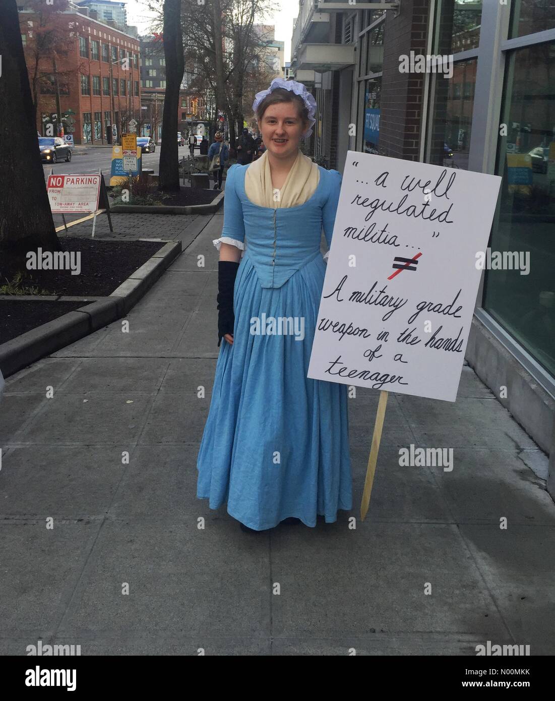 Woman dressed as a suffragette holding protest poster on Seattle street ...