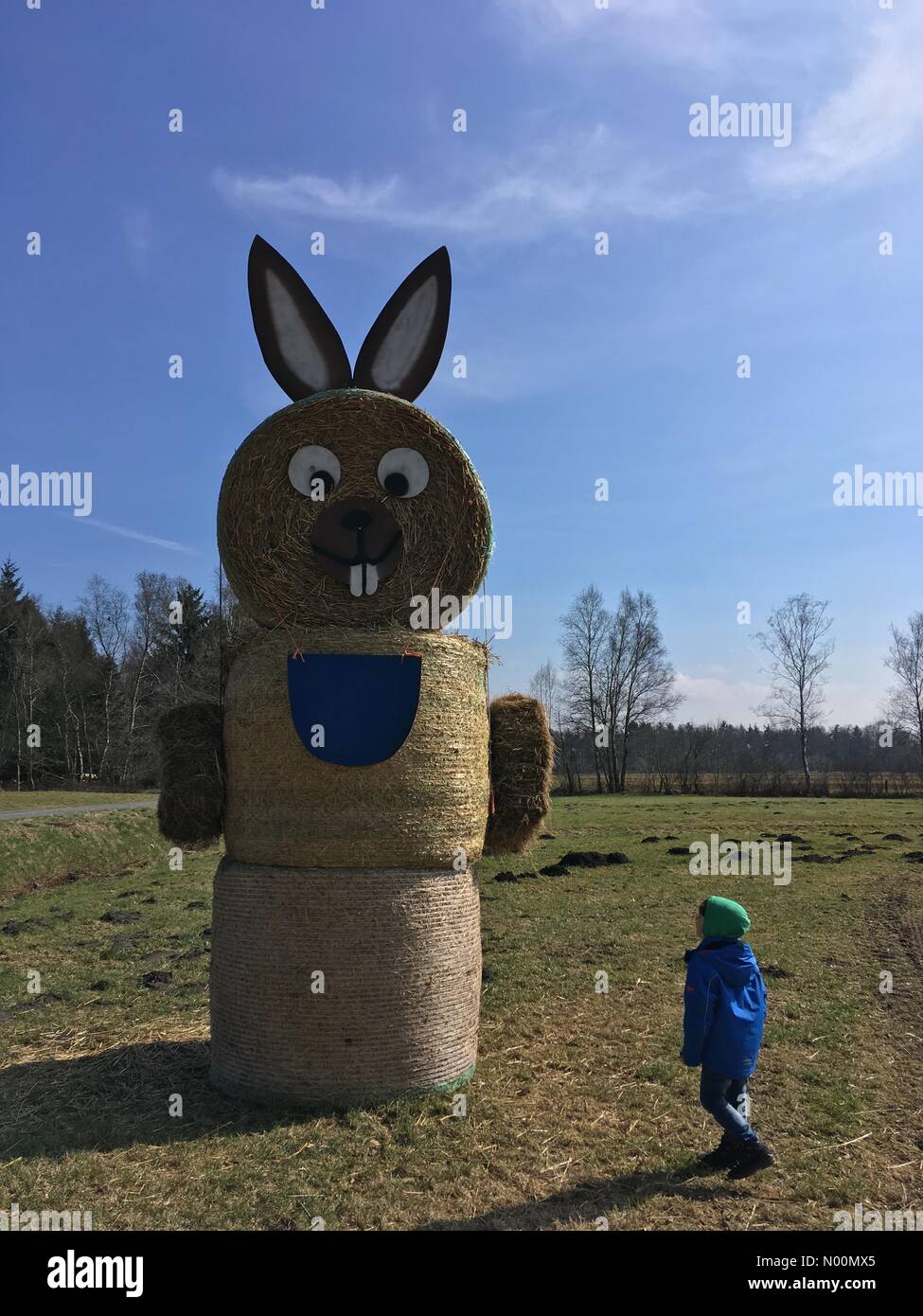 Young boy looking at Easter bunny made out of hay bales close to ...