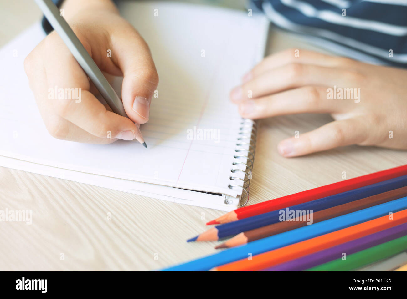 Kid holding pencil and writing in notebook. Close up Stock Photo - Alamy