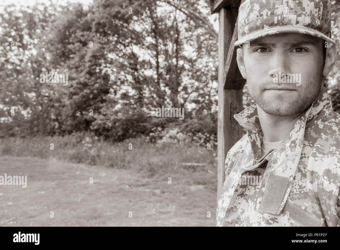 Muscular military man in army fatigues and cap stands to attention ...