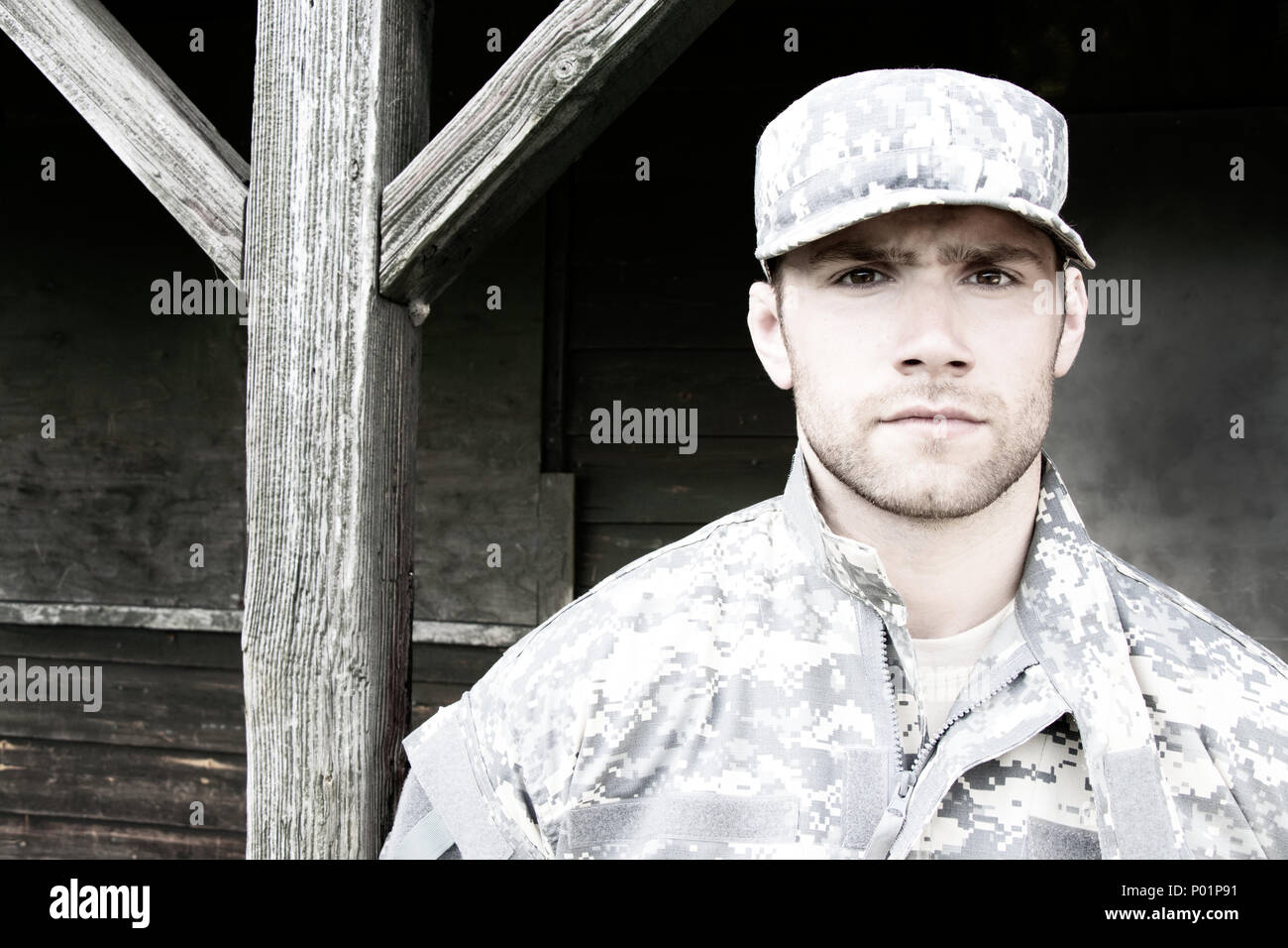 Muscular military man in army fatigues and cap stands to attention ...