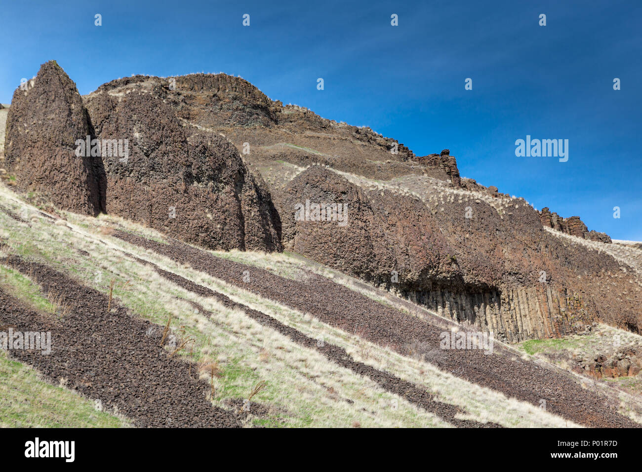 Columnar basalt rocks form a steep hillside with erosion creating ...