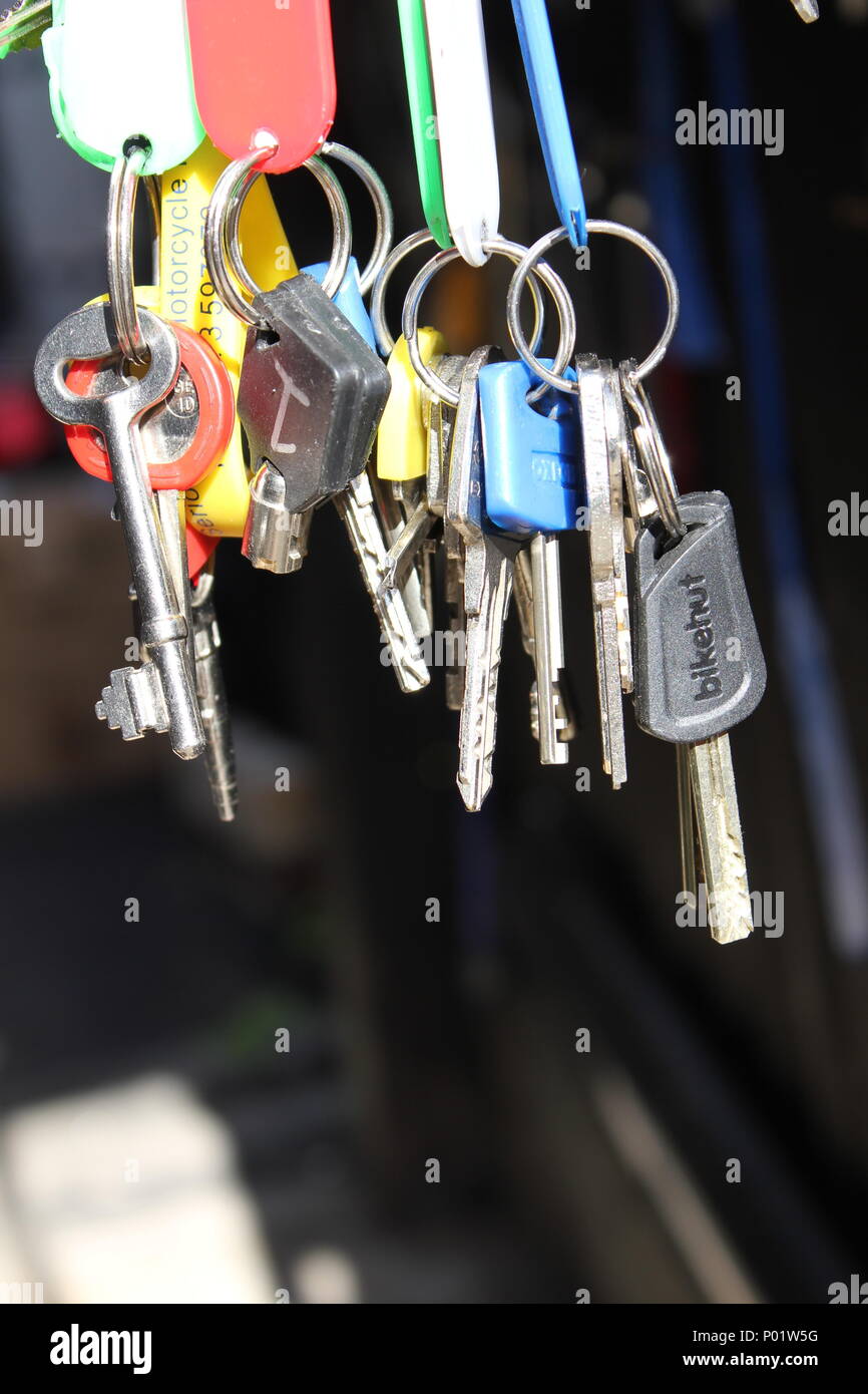 A variety of silver keys hanging from colourful fobs against a black ...