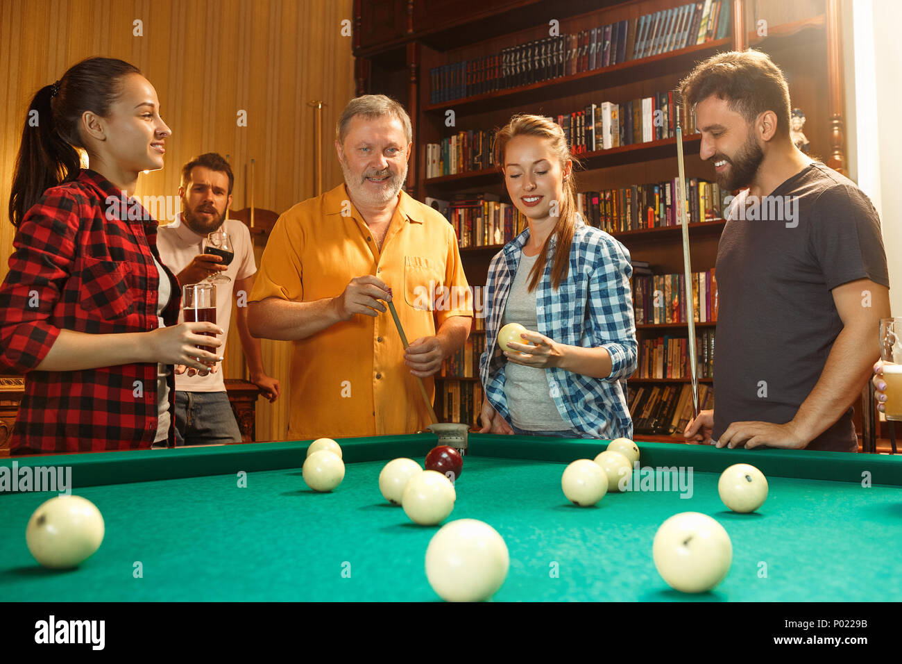 Young men and women playing billiards at office after work Stock Photo ...