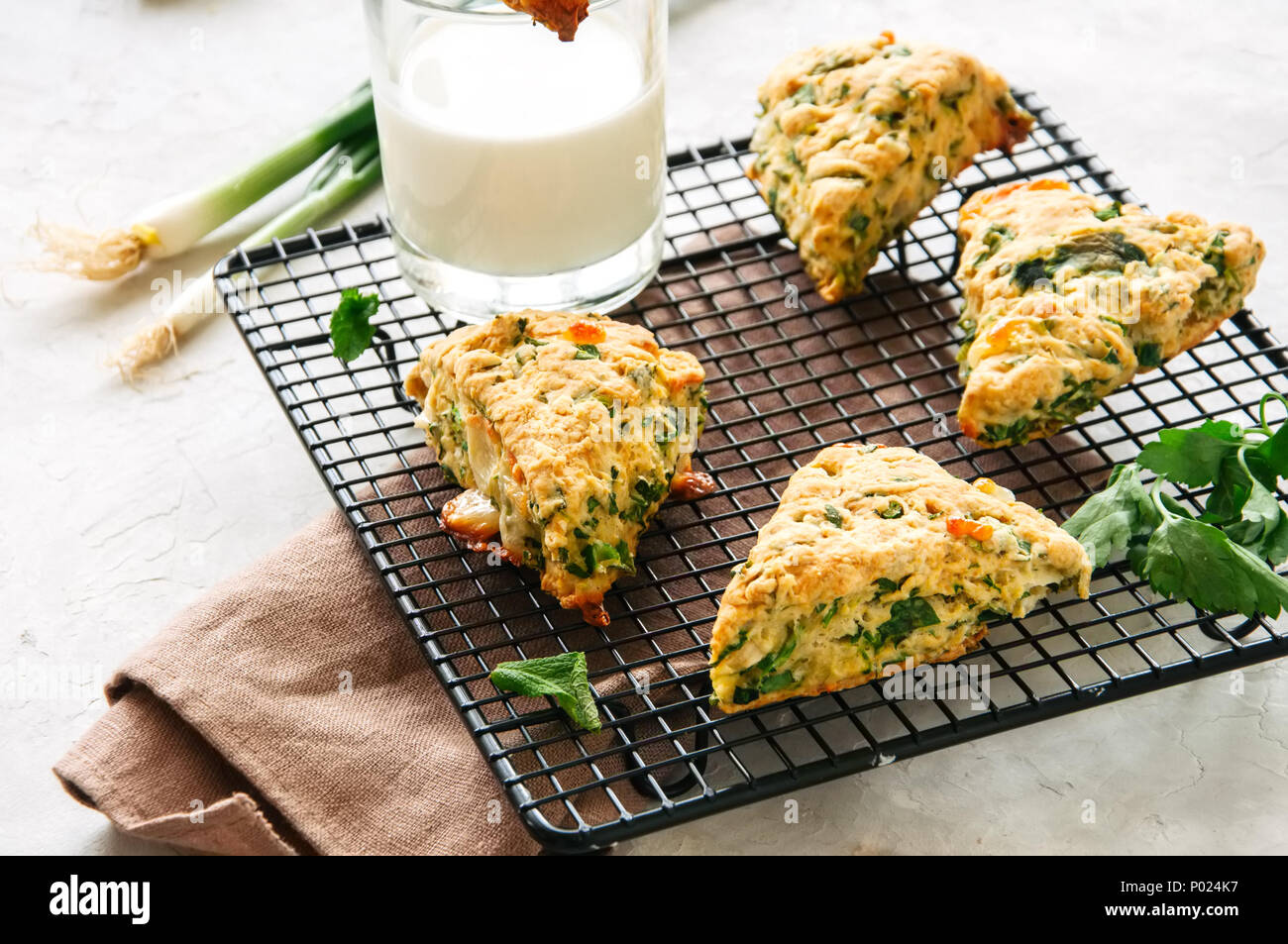 Savory scones with feta mozarella and green herbs on a wire rack. White ...