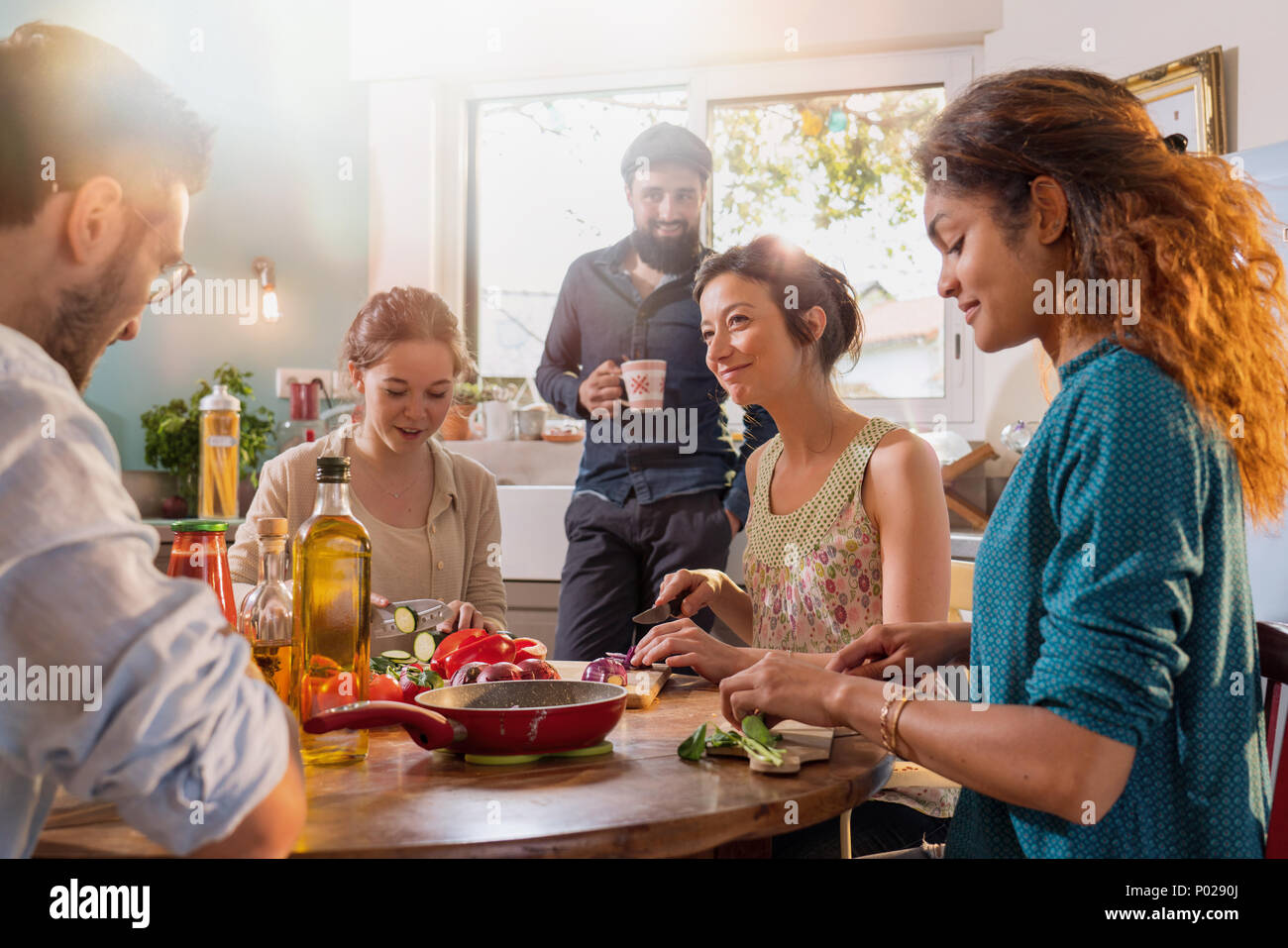 Multi-ethnic group of friends cooking lunch in the kitchen Stock Photo ...