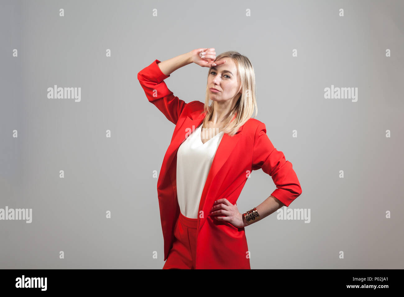 Young beautiful white blond girl in a bright red strict suit with a ...