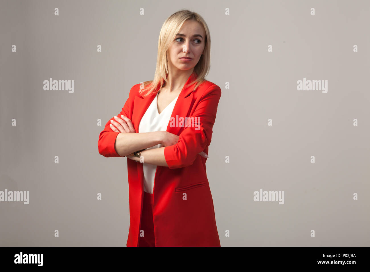 Young beautiful white blond girl in a bright red strict suit with a ...