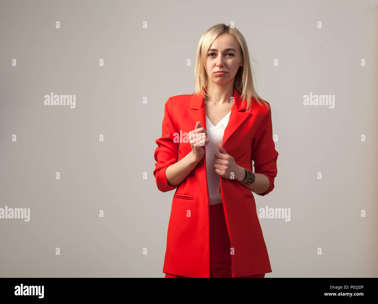 Young beautiful white blond girl in a bright red strict suit with a ...